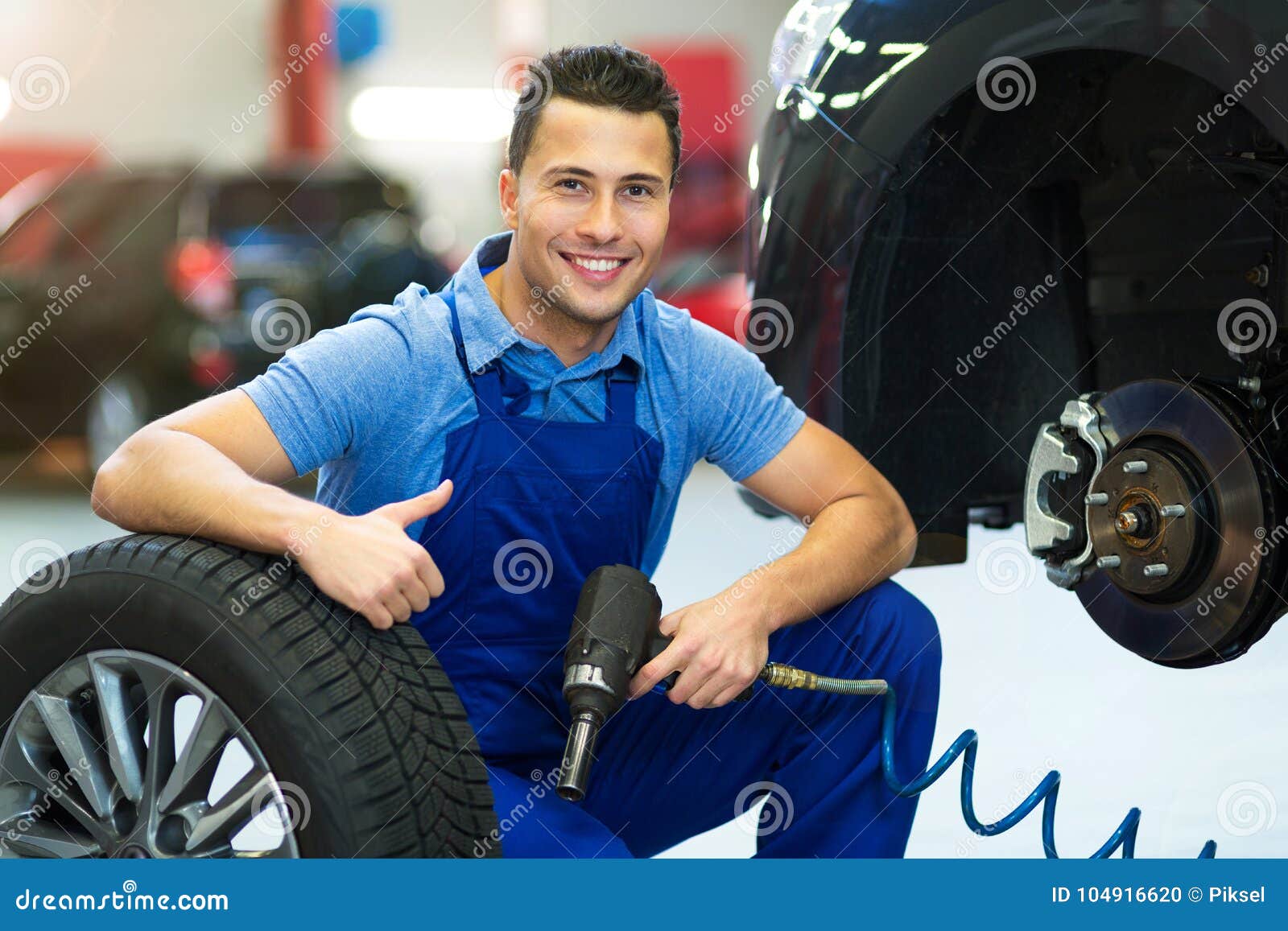 Car Mechanic Crouching Down by a Tire Stock Photo - Image of ...
