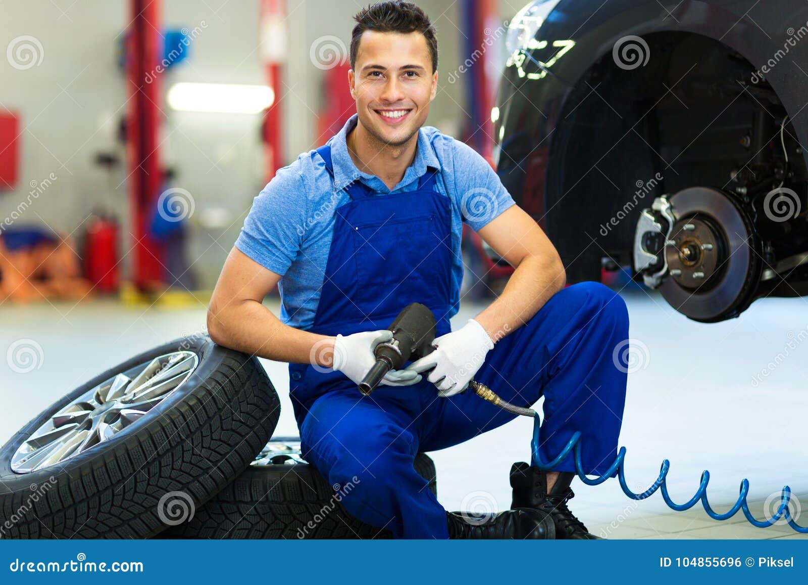 Car Mechanic Crouching Down by a Pair of Wheels Stock Photo - Image of ...