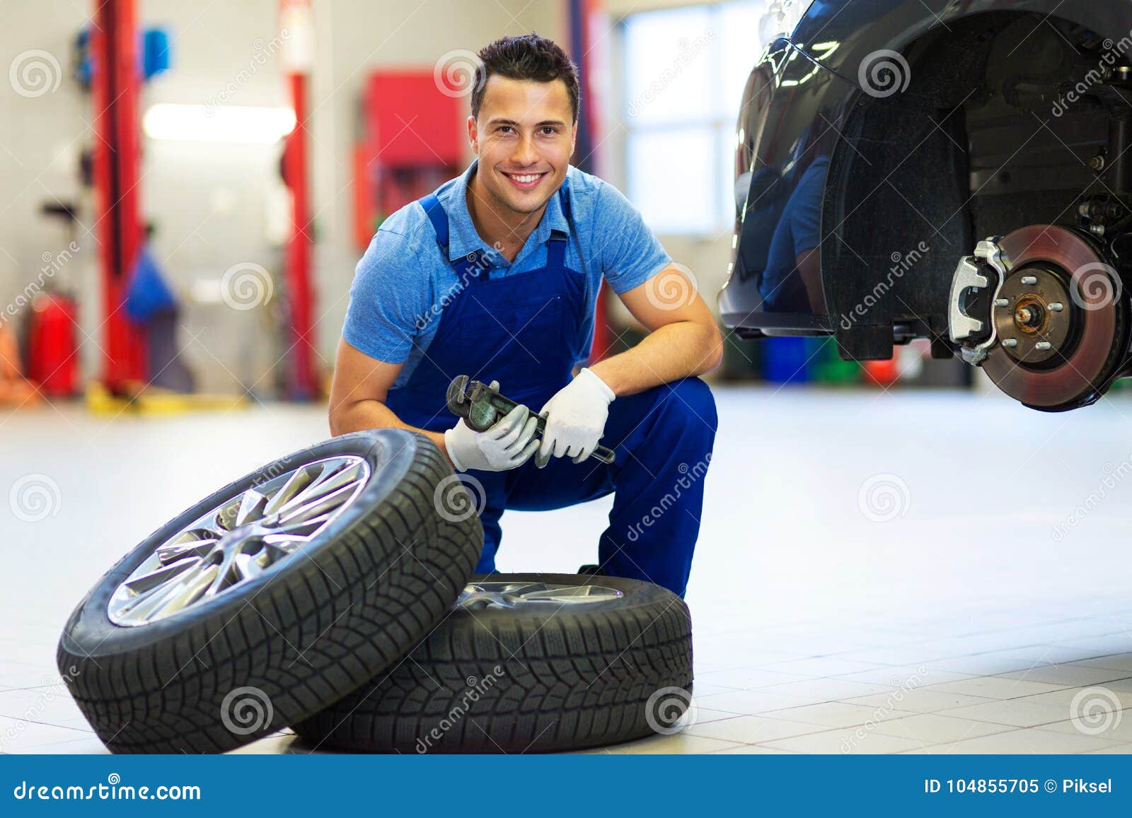Car Mechanic Crouching Down by a Pair of Wheels Stock Image - Image of ...