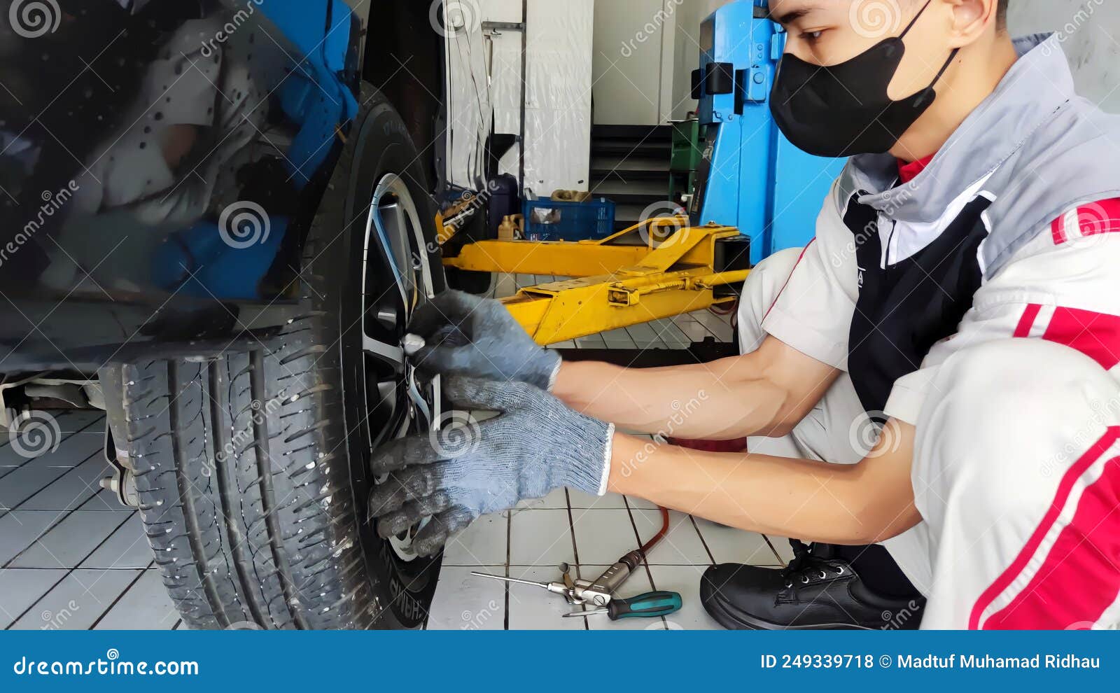 A Car Mechanic is Installing a Wheel on a Car Stock Photo - Image of ...