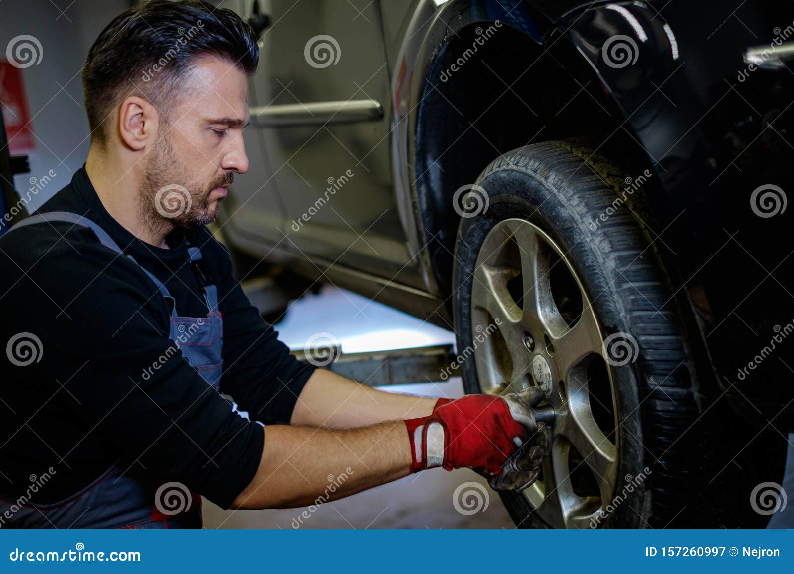 Car Mechanic Replacing Wheel in a Workshop Stock Image - Image of ...