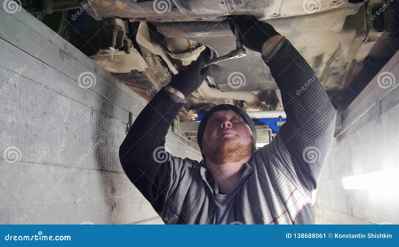 Car Service. Thick Mechanic Man Standing in Inspection Pit and Working ...