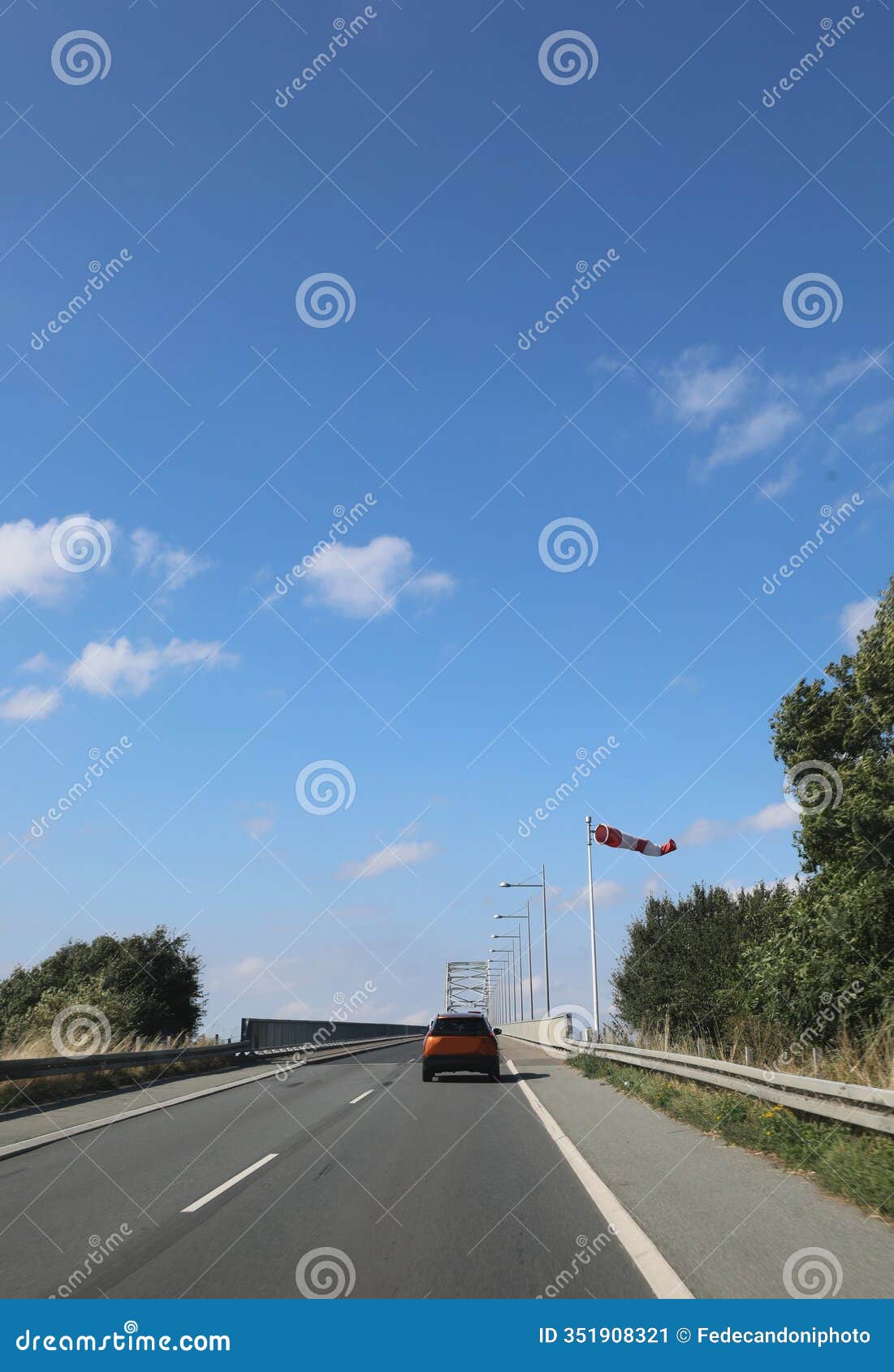 Car Speeding Over a Bridge and a Windsock Indicating the Direction ...