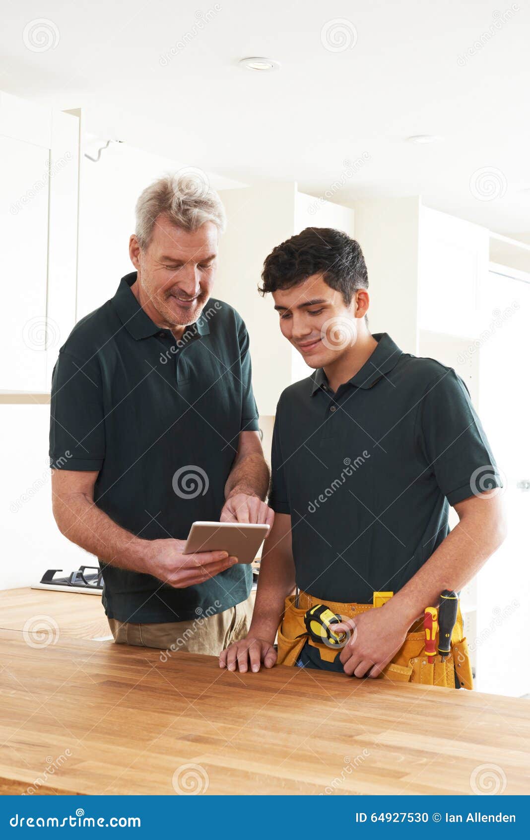 Carpenter and Apprentice with Digital Tablet Fitting Luxury Kitchen ...