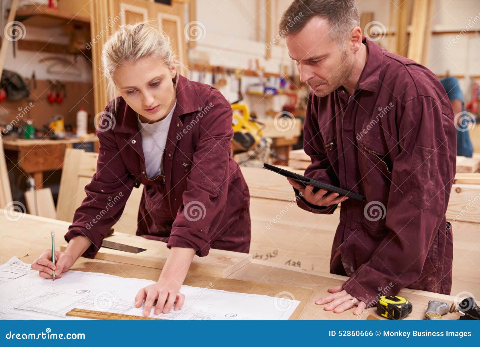 Carpenter with Apprentice Looking at Plans in Workshop Stock Photo ...