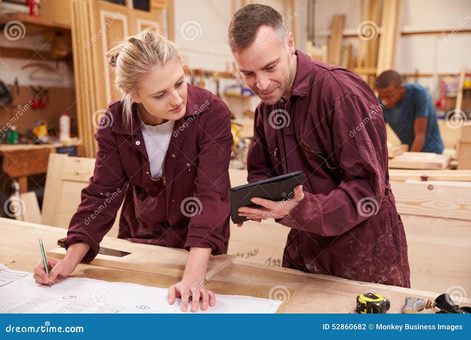 Carpenter with Apprentice Looking at Plans in Workshop Stock Photo ...