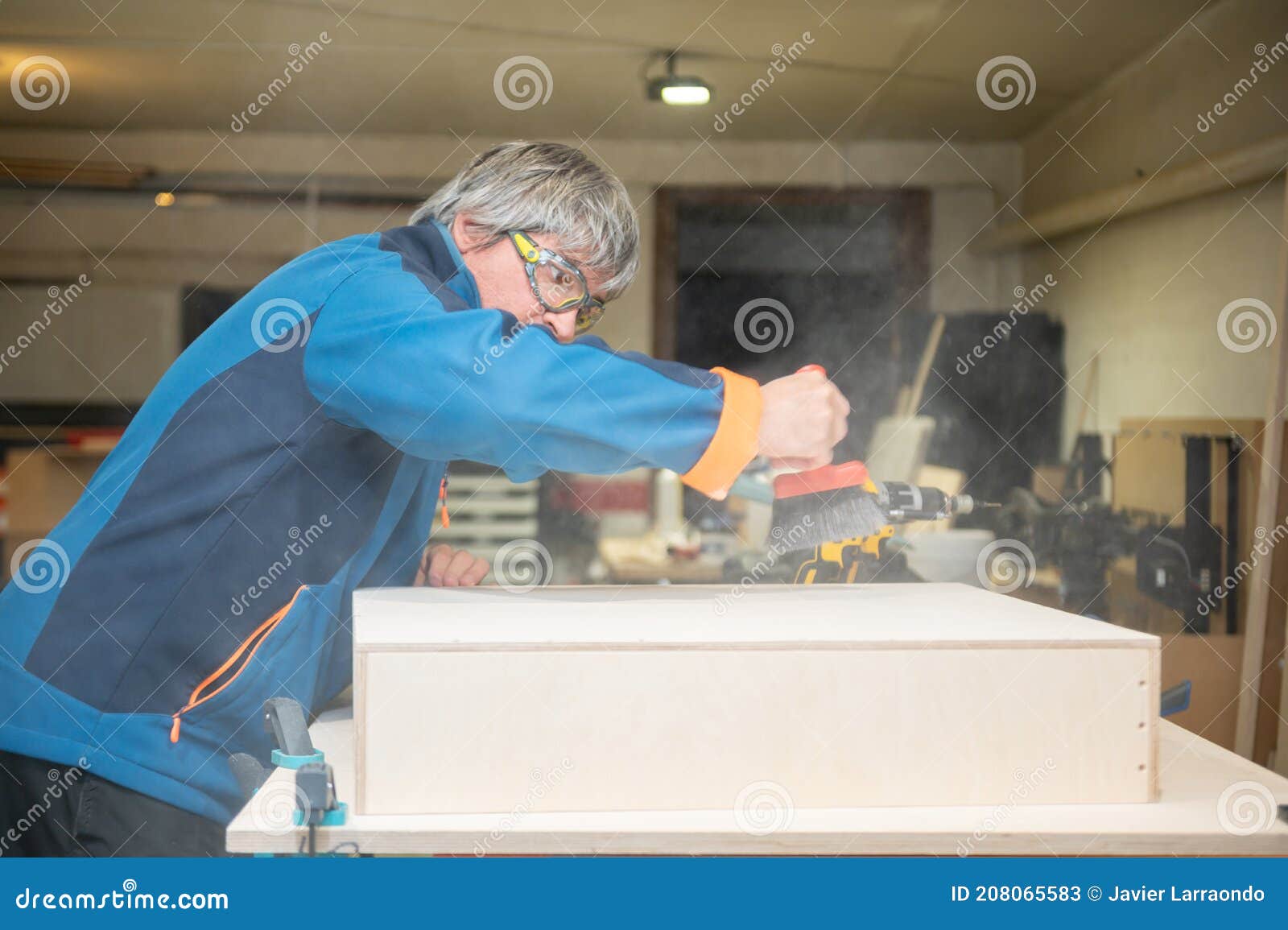 Carpenter Cleans the Wood with a Brush Raising Dust in His Workshop ...