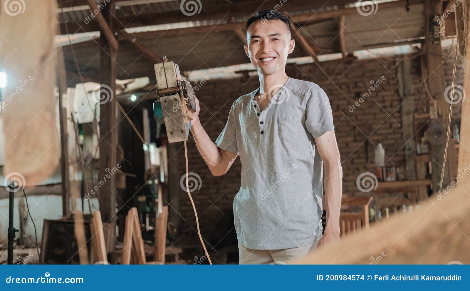 Carpenter Stands Holding a Wooden Stake Smiling when he Sees the Camera ...