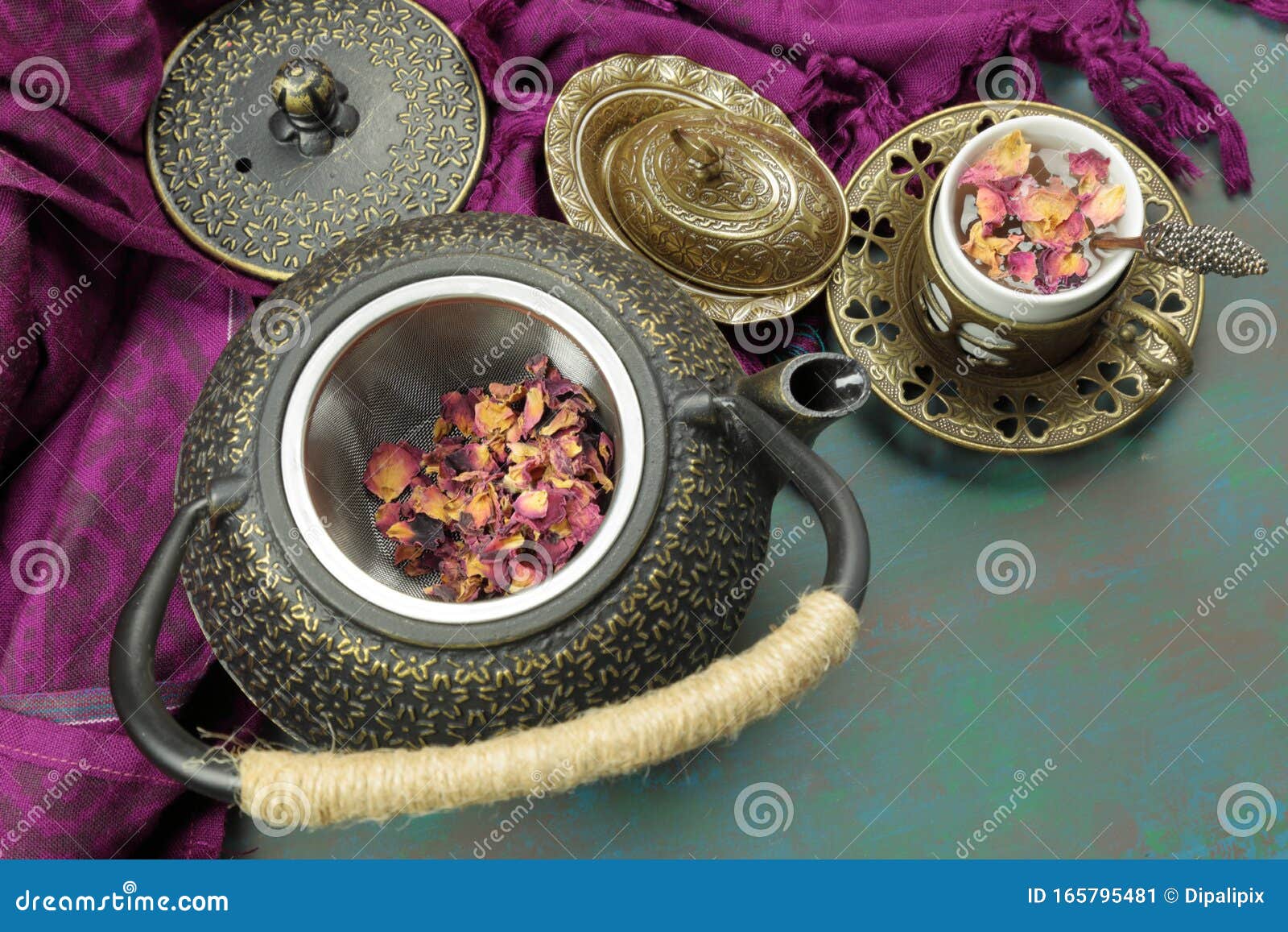 A Cast Iron Teapot Kettle with a Cup of Rose Tea and Some Rose Petals ...
