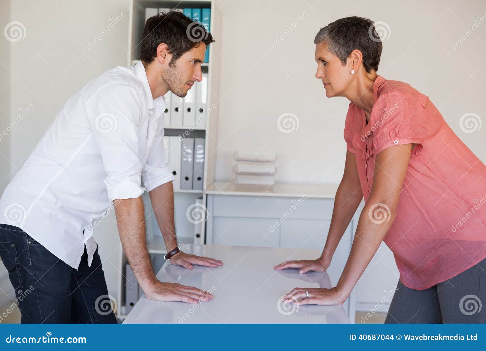 Casual Business Team Facing Off at Desk Stock Photo - Image of ...