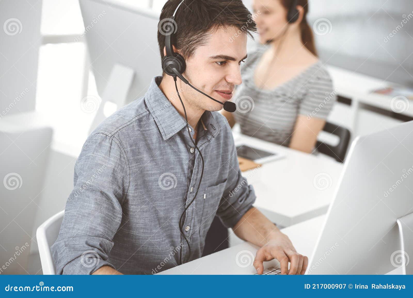 Casual Dressed Young Man Using Headset and Computer while Talking with ...