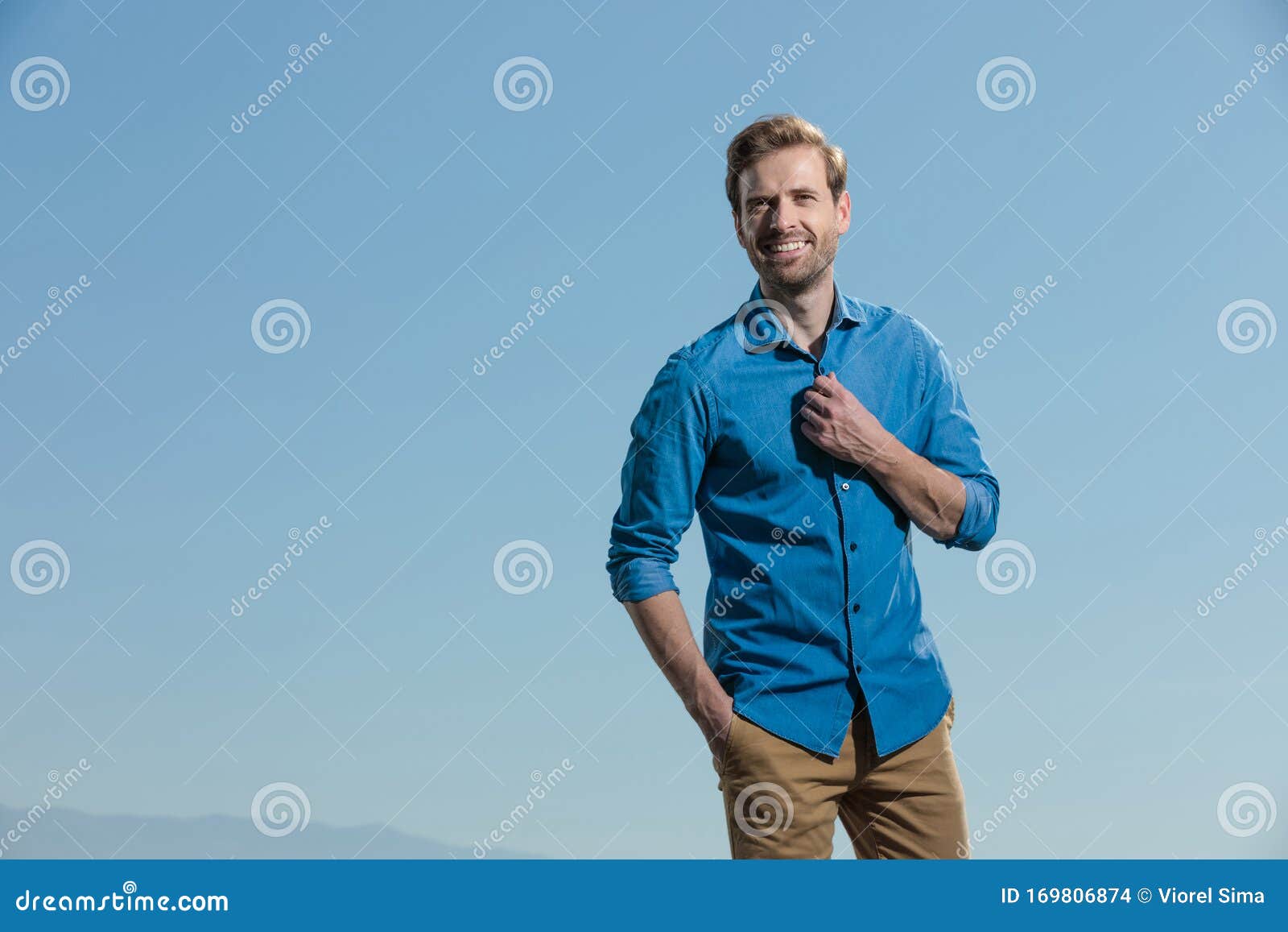 Casual Man Standing with Hand in Pocket Fixing Shirt Stock Photo ... Casual Man Standing with Hand in Pocket Fixing Shirt Stock Photo ...