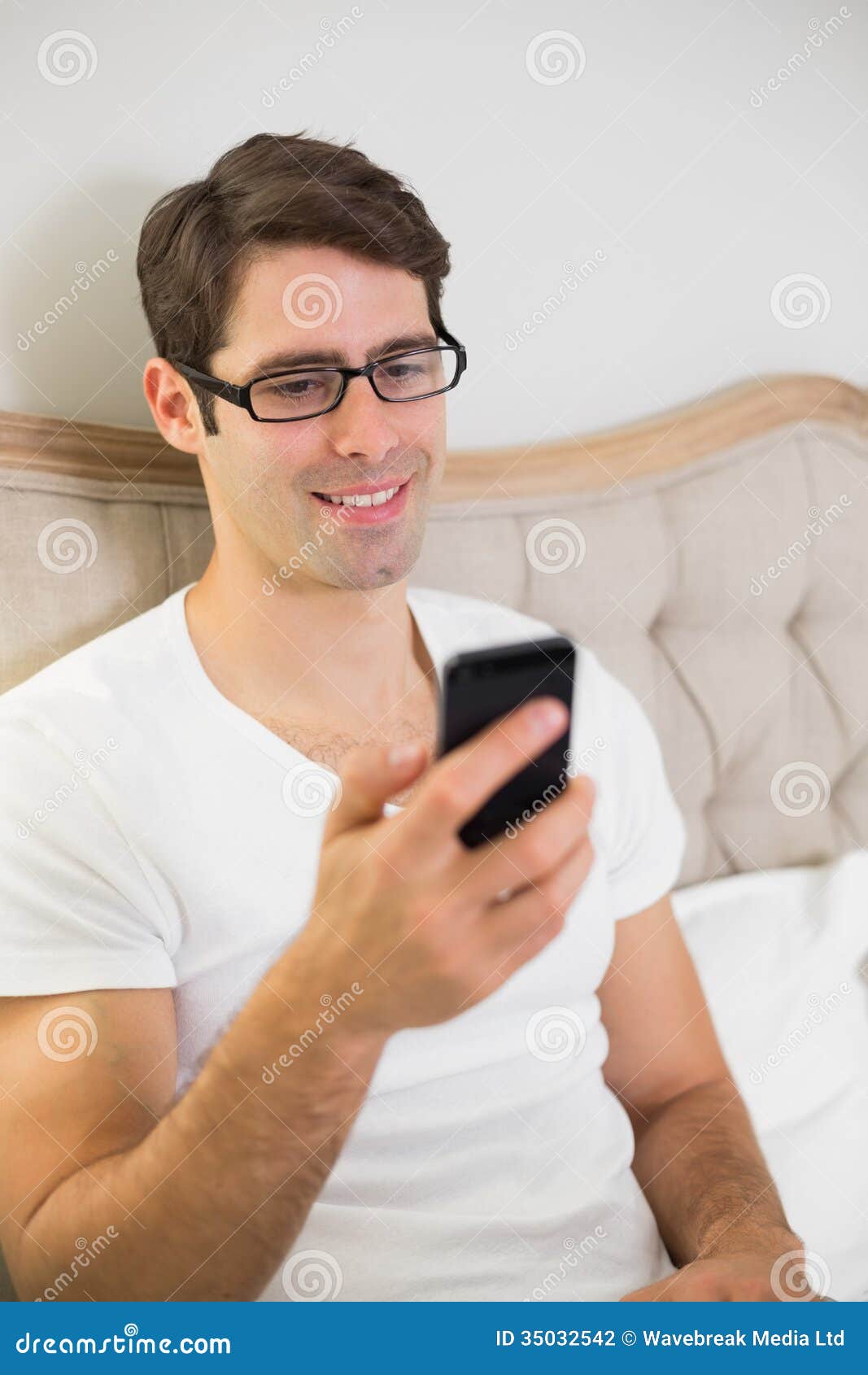 Casual Smiling Young Man Text Messaging in Bed Stock Photo - Image of ...