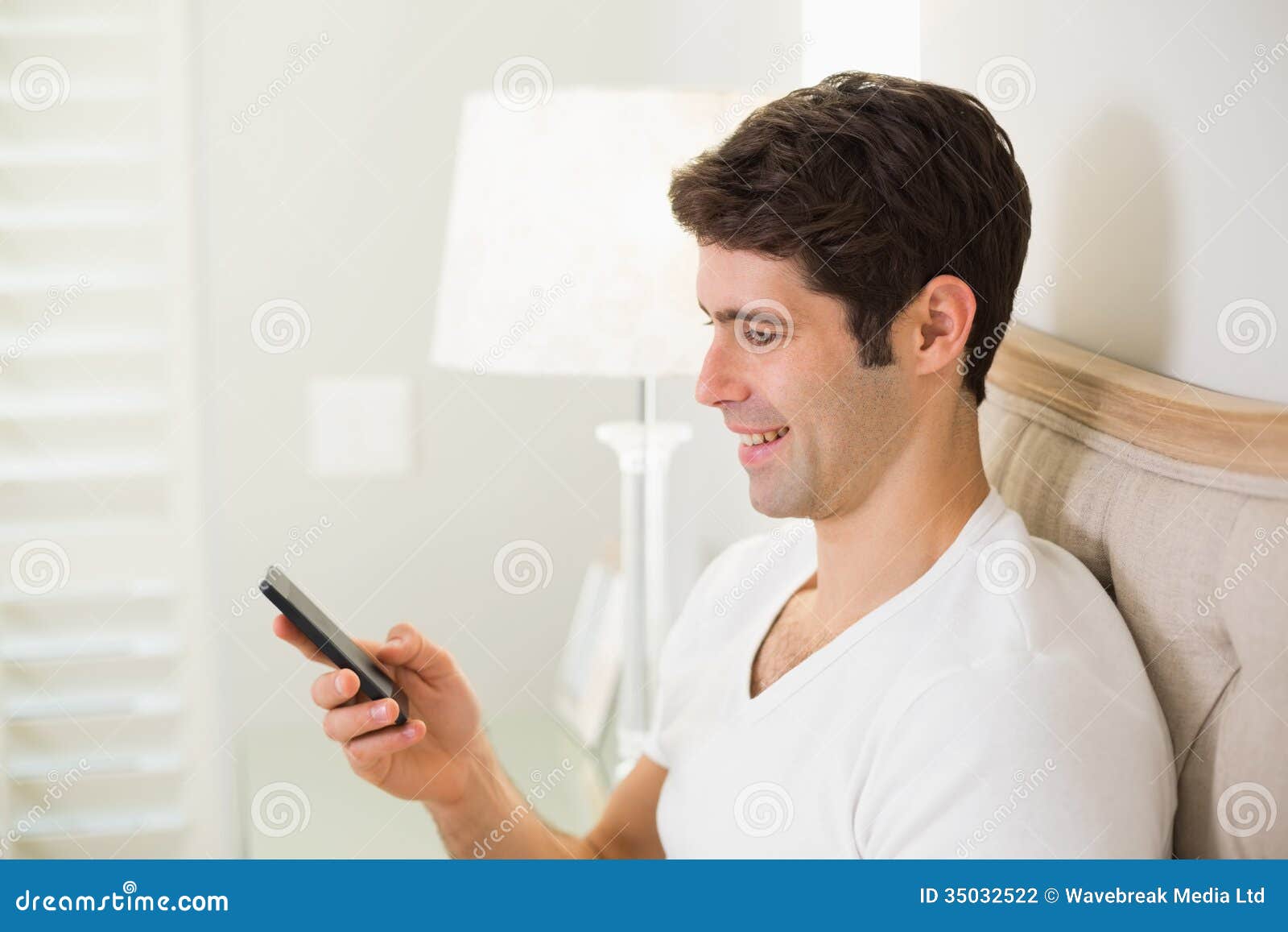 Casual Smiling Young Man Text Messaging in Bed Stock Photo - Image of ...