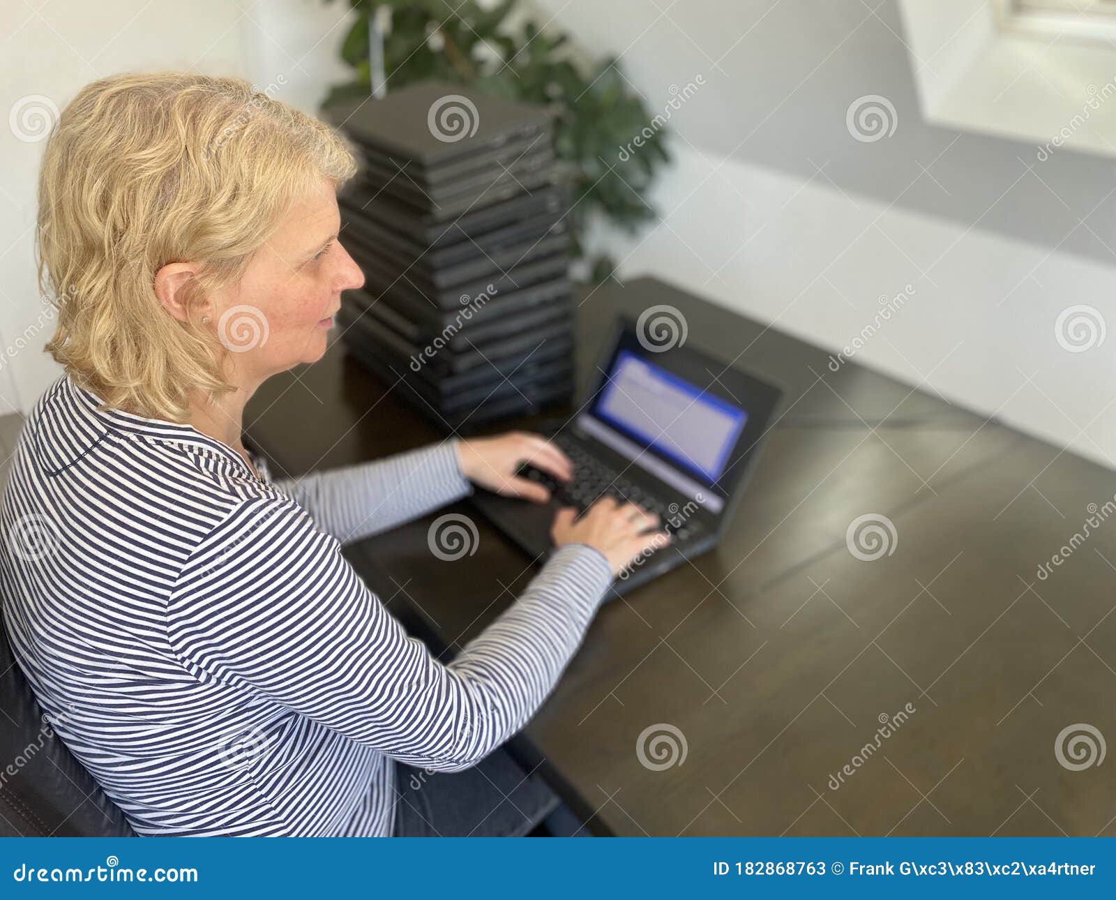 A Casually Dressed Caucasian Middle Aged Woman is Installing a Laptop ...