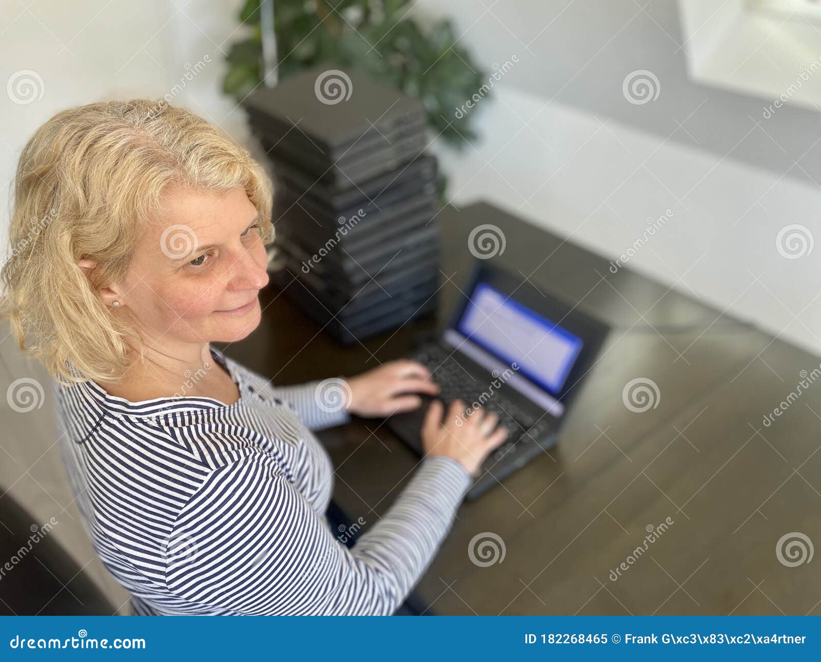 A Casually Dressed Caucasian Middle Aged Woman is Installing a Laptop ...