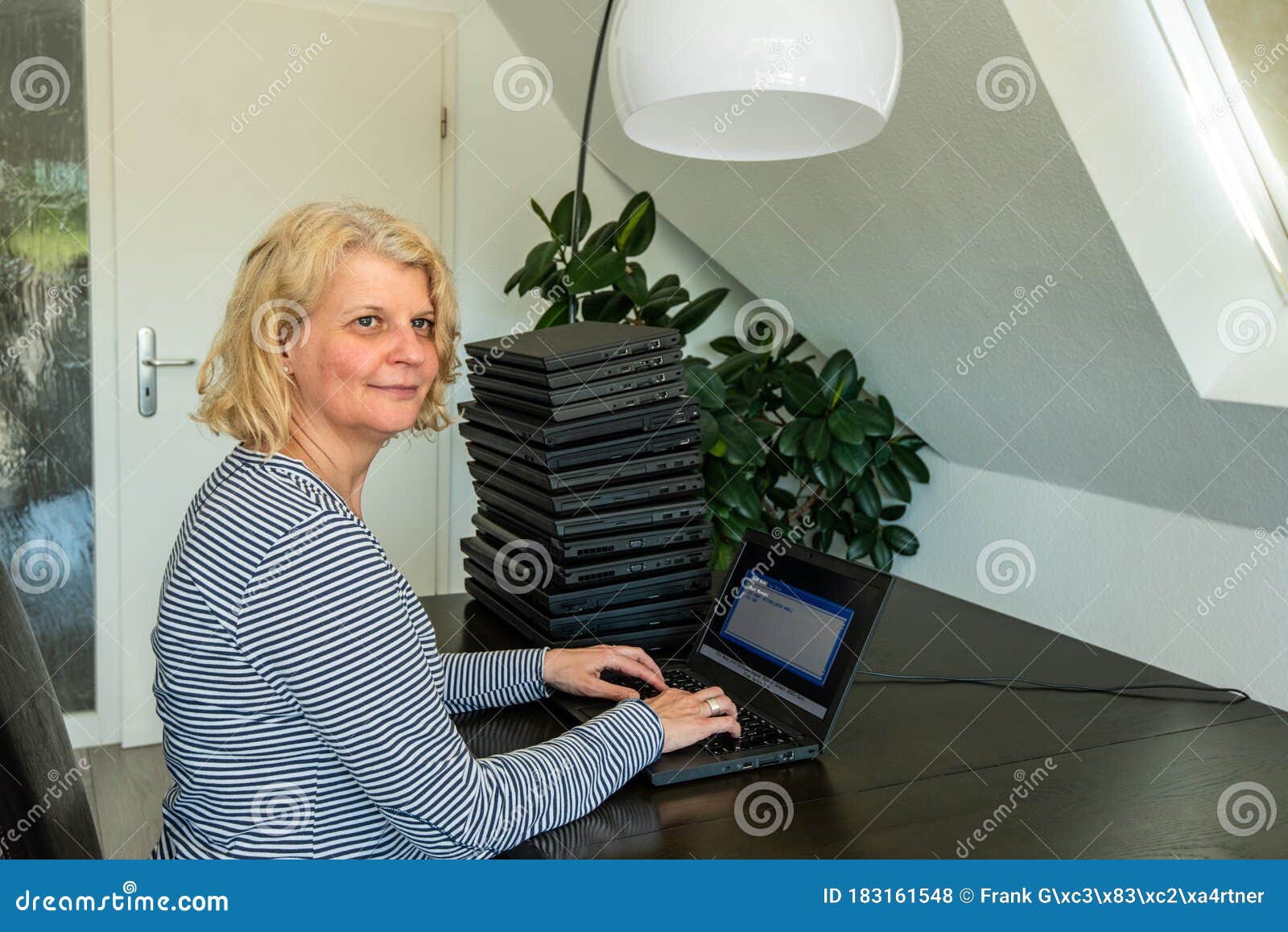 A Casually Dressed Caucasian Middle Aged Woman is Installing a Laptop ...
