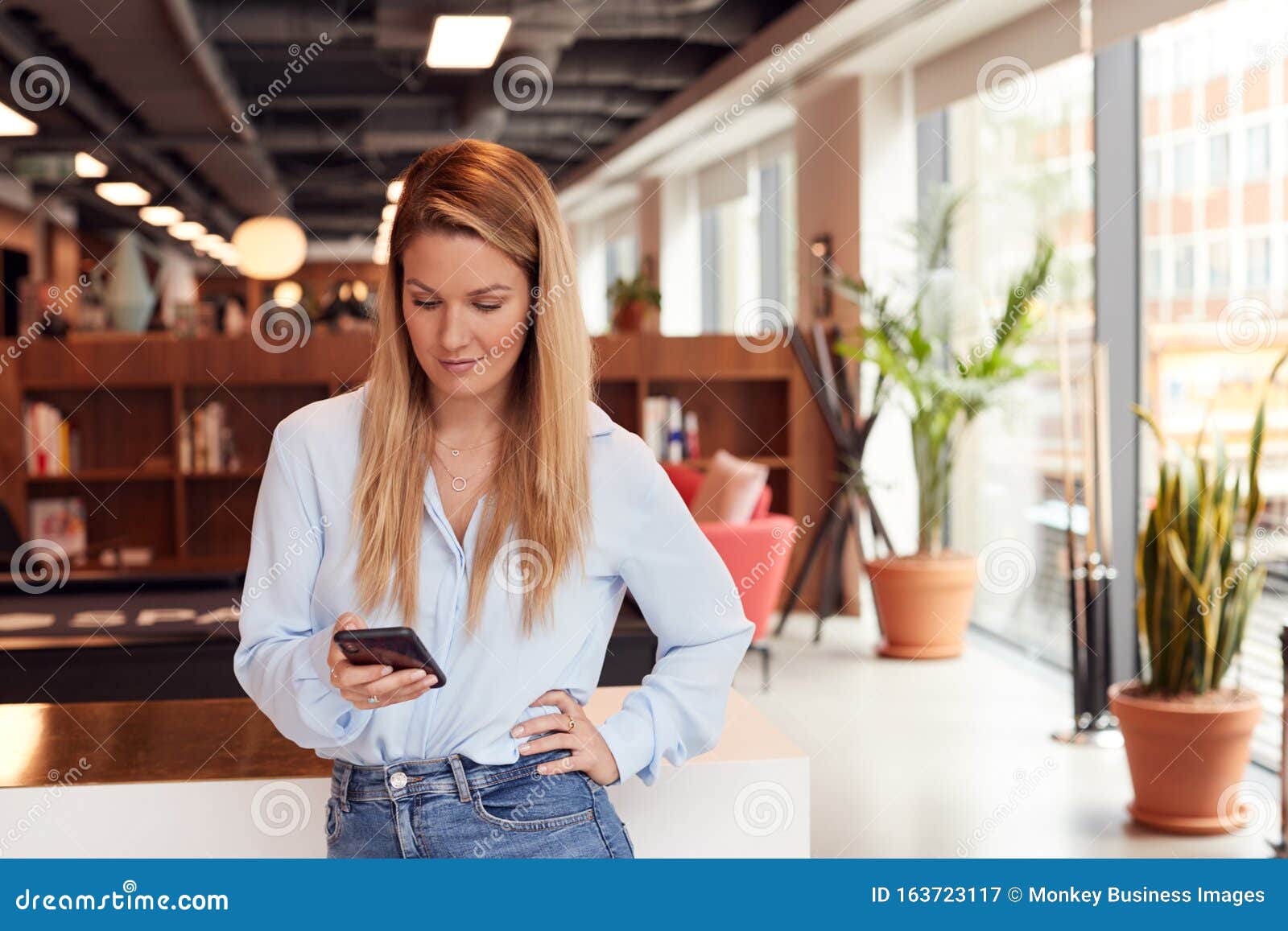 Casually Dressed Young Businesswoman Checking Mobile Phone in Modern ...