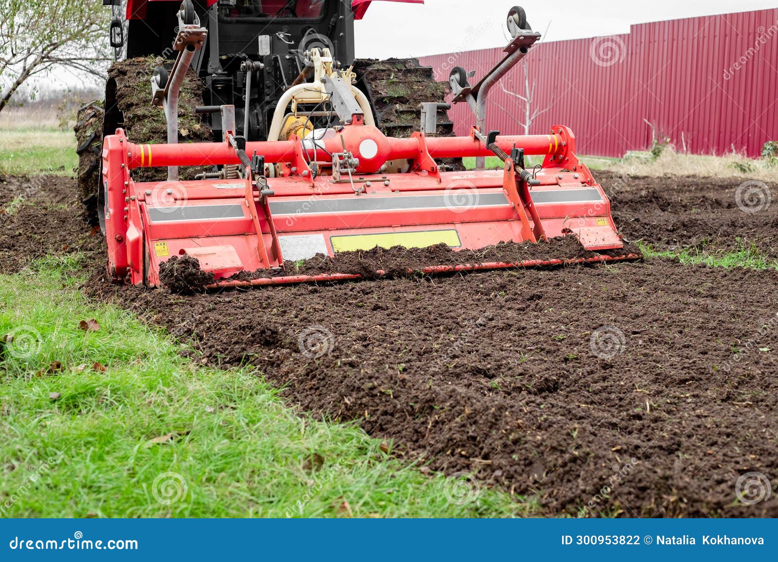 Caterpillar Tractor with a Tillage Cutter Loosens the Soil in a Garden ...