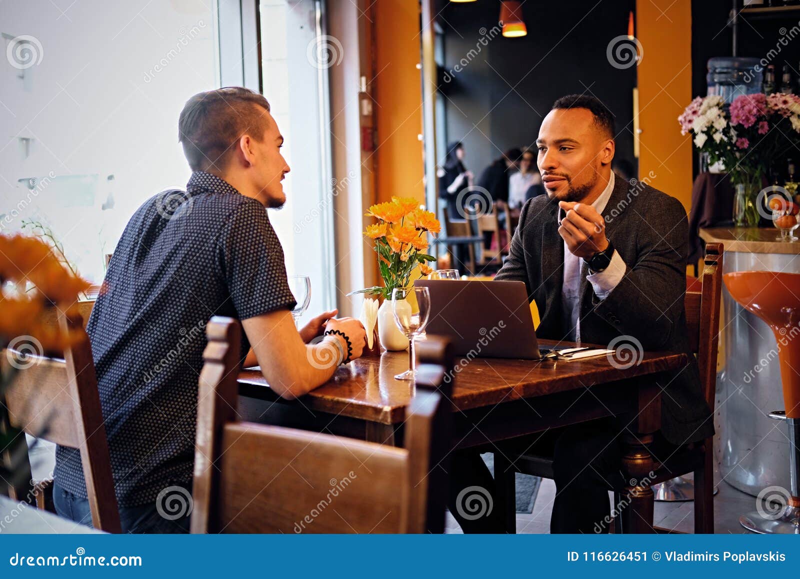 Two Men Talks and Using a Laptop in a Restaurant. Stock Image - Image ...