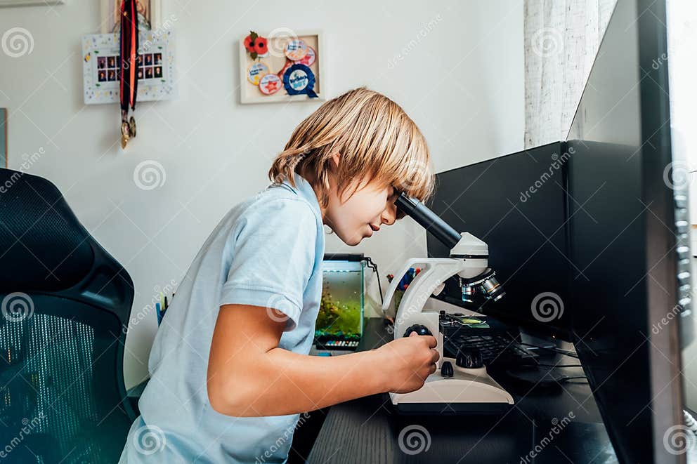 Caucasian Boy Using a Microscope at Home at His Study Place. Child ...