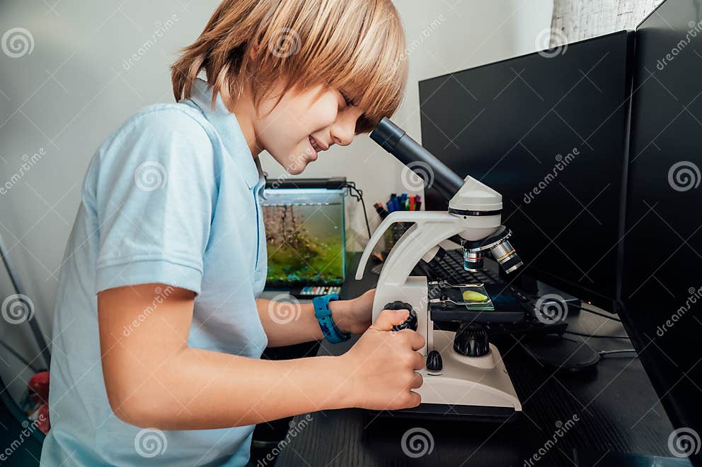 Caucasian Boy Using a Microscope at Home at His Study Place. Child ...