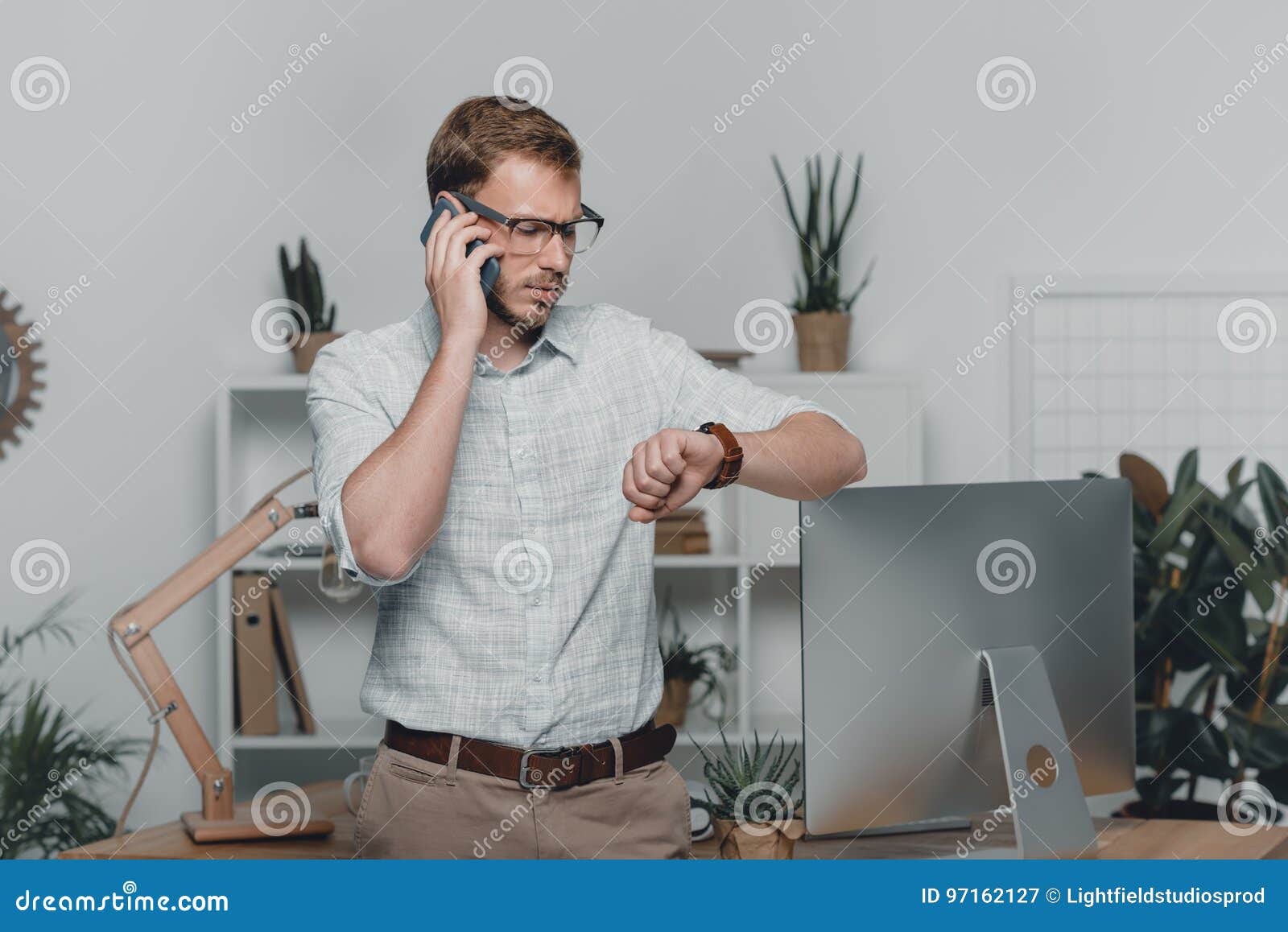 Caucasian Businessman Using Smartphone and Looking on Watch in Modern ...