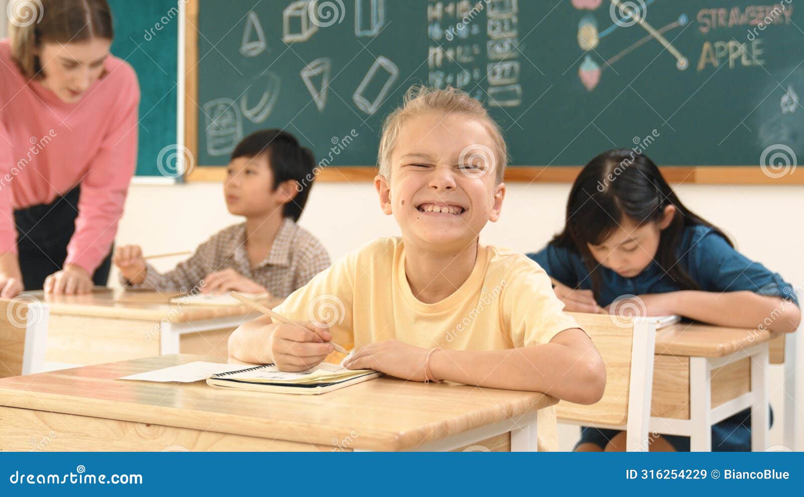 Caucasian Child Smiling at Camera while Doing Classwork at Classroom ...