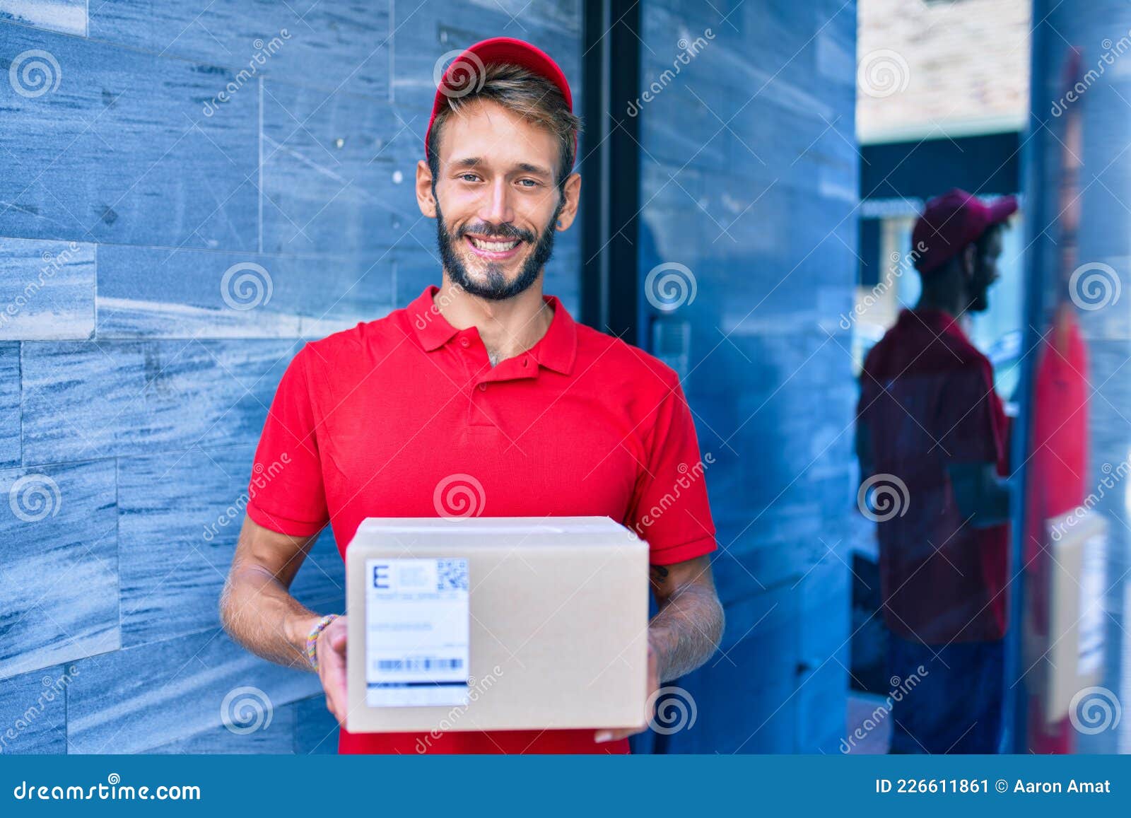 Caucasian Delivery Man Wearing Red Uniform and Delivering Parcel Stock ...