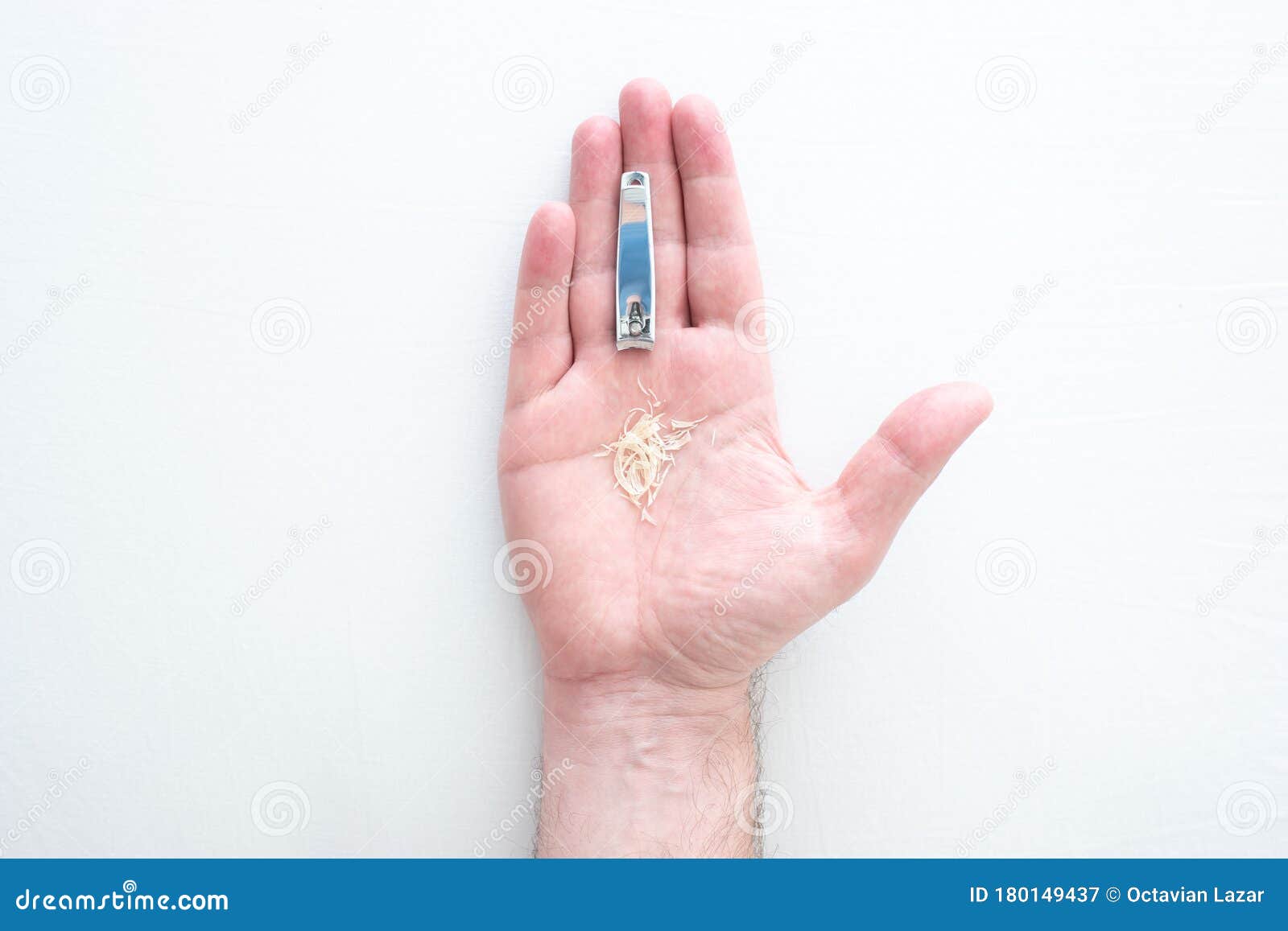 Caucasian Male Hand Holding A Metal Nail Clipper And Some Cut Nails On
