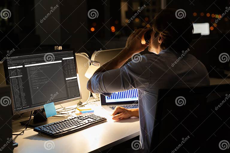 Caucasian Male Programmer Sitting at Desk, Drinking Coffee, Using Computer with Coding on Screen ...