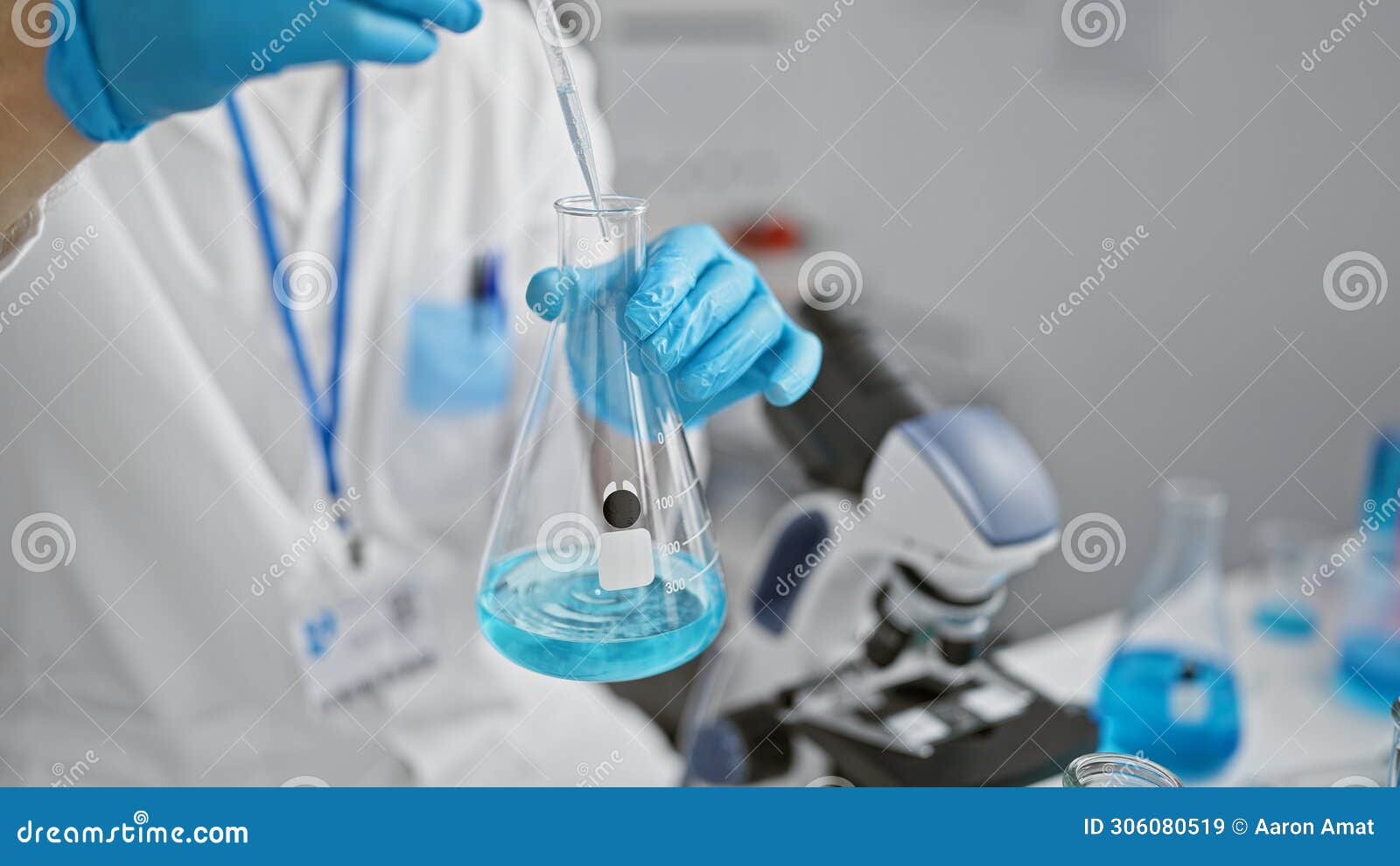 Caucasian Male Scientist Pipetting Blue Liquid into a Flask in a ...