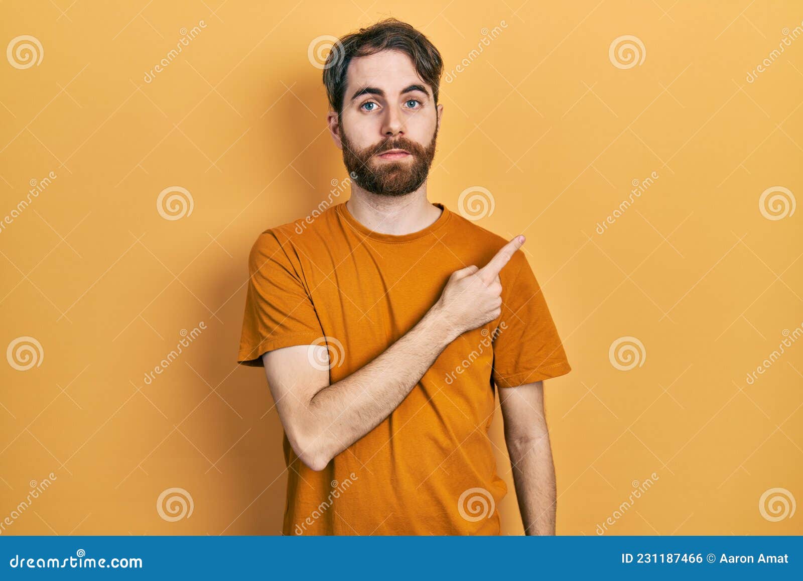 Caucasian Man With Beard Wearing Casual Yellow T Shirt Pointing With
