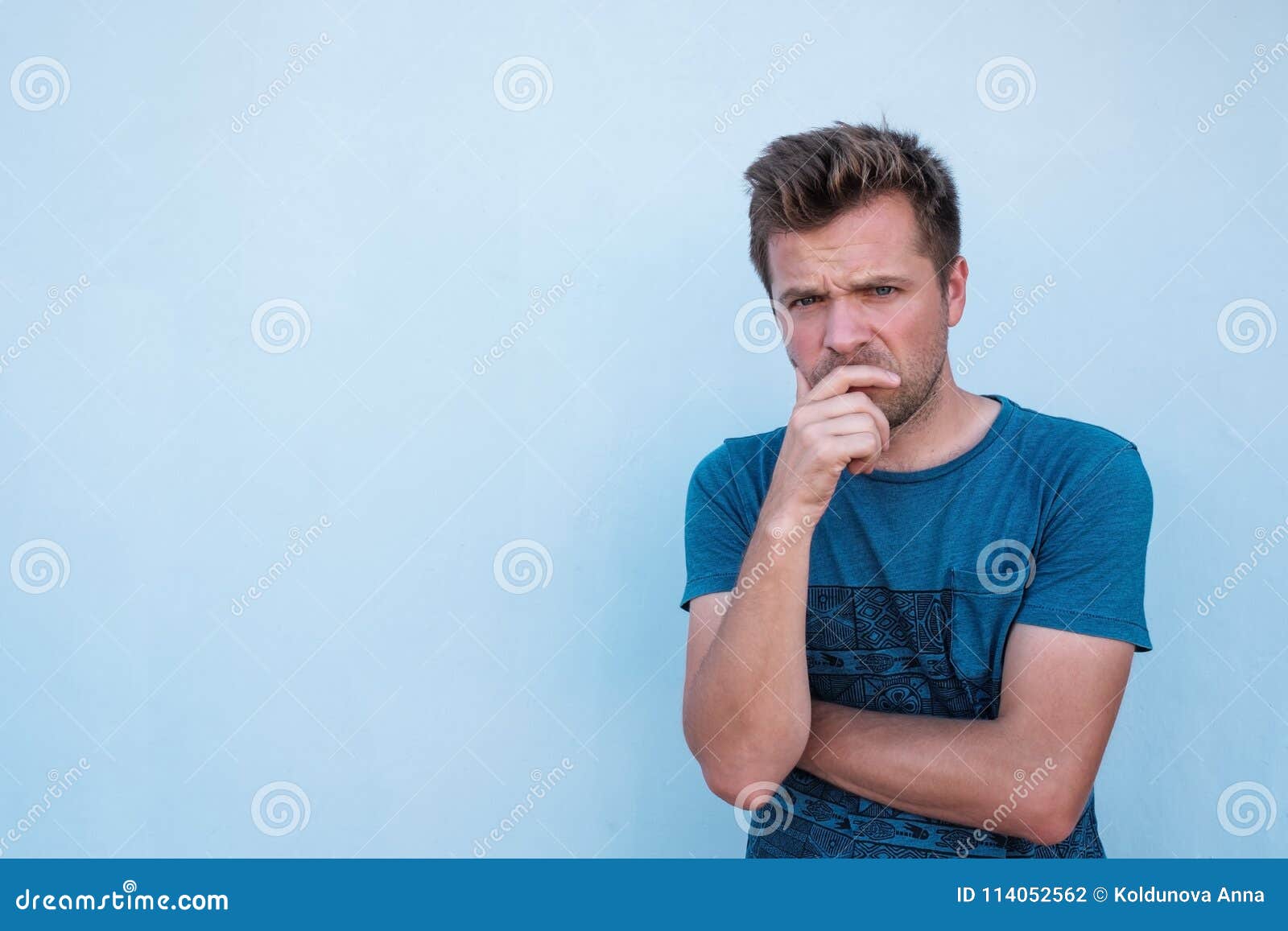 Caucasian Man Standing Near Blue Wall with Pensive Expression on His ...