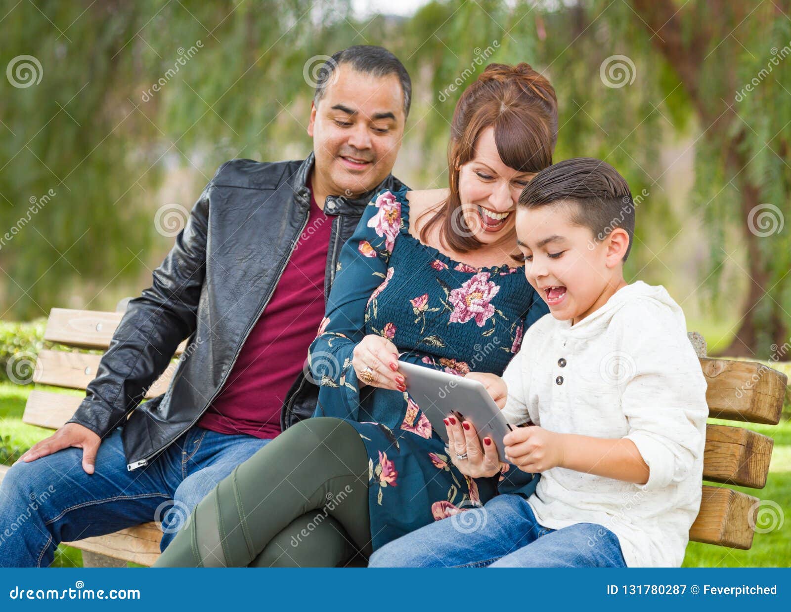Excited Caucasian Mother and Hispanic Father Using Computer Tablet with ...