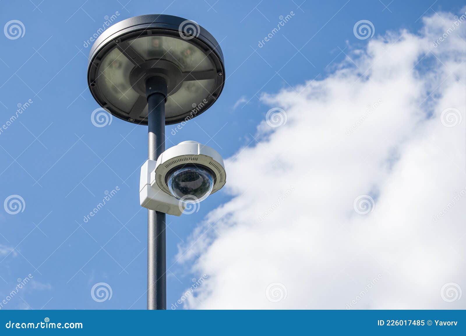 A CCTV Camera is Mounted on a Pillar with a Blue Sky and Clouds in the ...