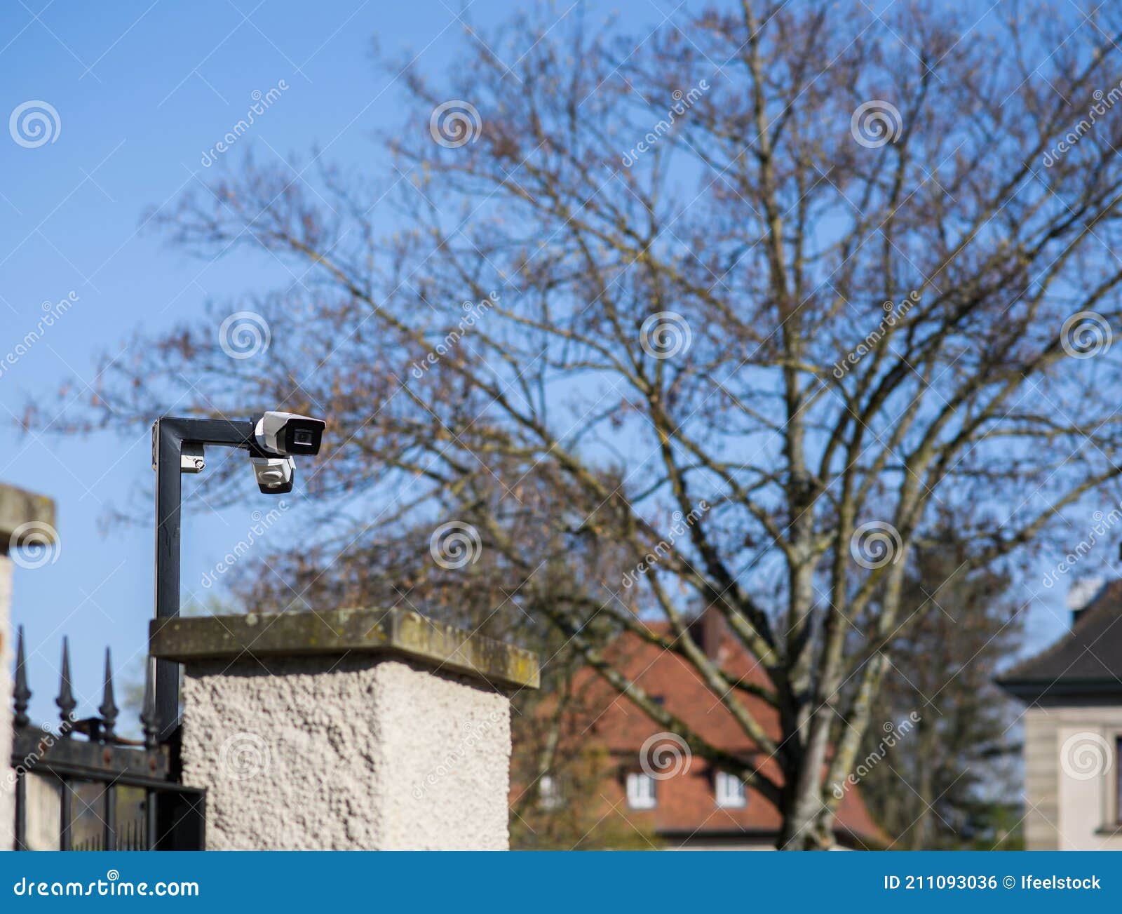 CCTV Camera on the Pole Surveilling the Area Behind Large Cement Fence ...