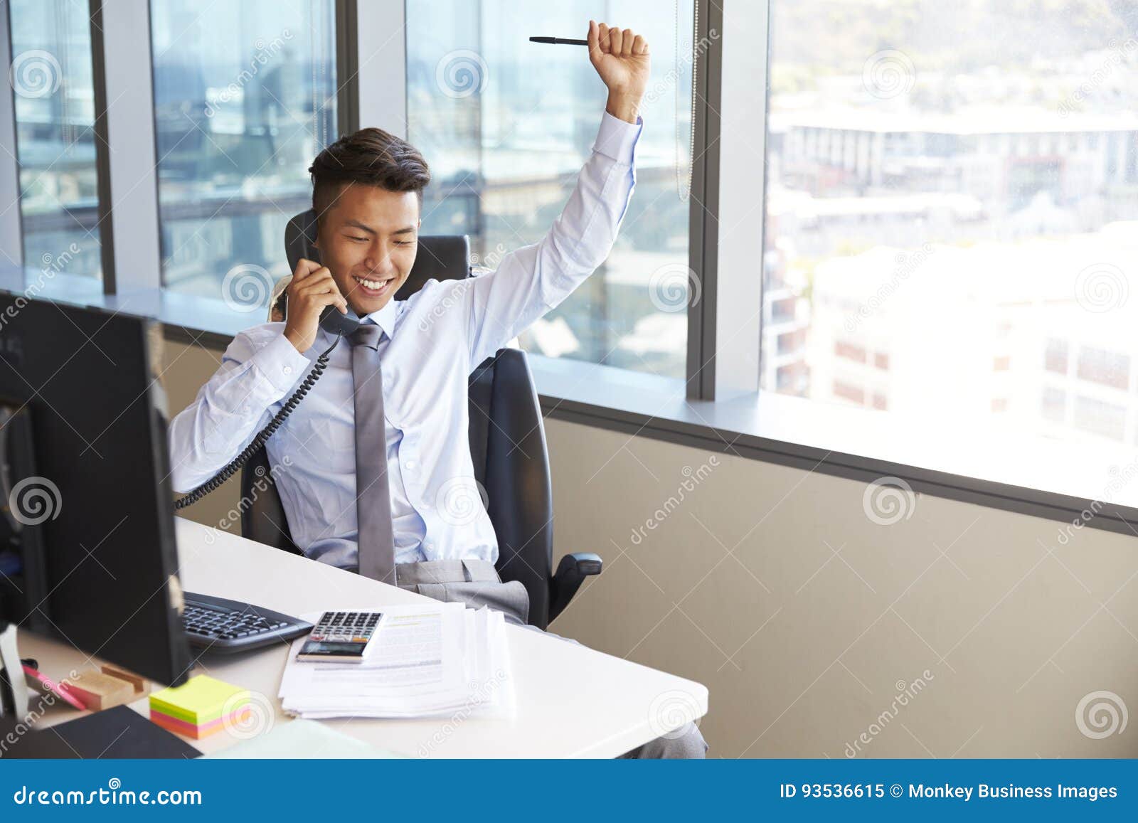 Celebrating Businessman Making Phone Call at Desk in Office Stock Image ...