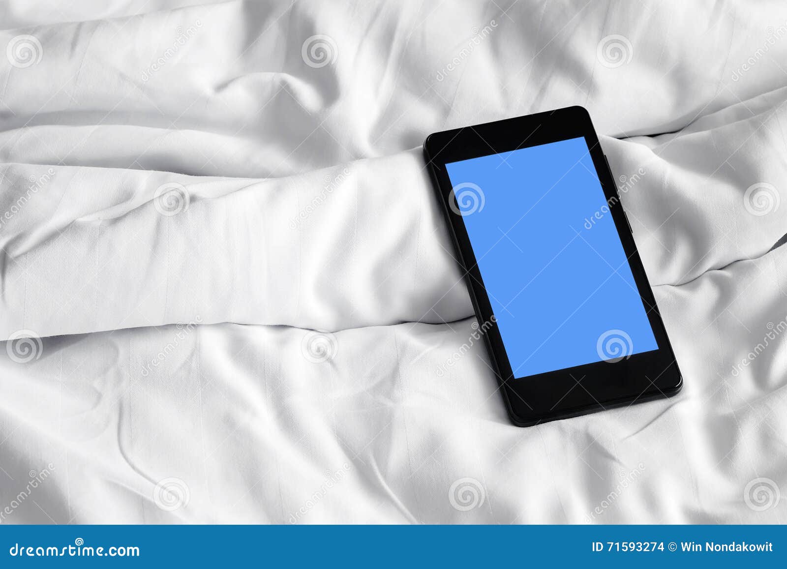 Cellphone on bed sheets stock photo. Image of material - 71593274