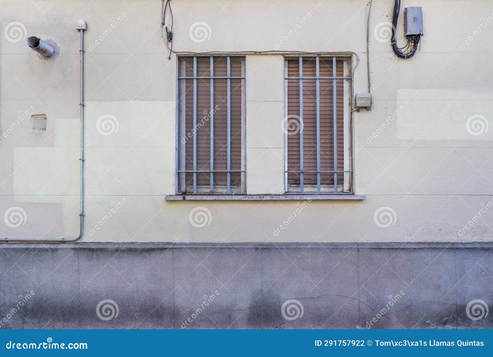 A Cement Wall with a Double Window with a Gray Painted Cross Grille ...