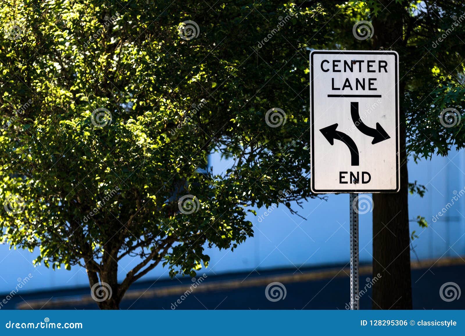 Center Lane Ends Sign with Trees, Road, and a Warehouse Stock Photo ...