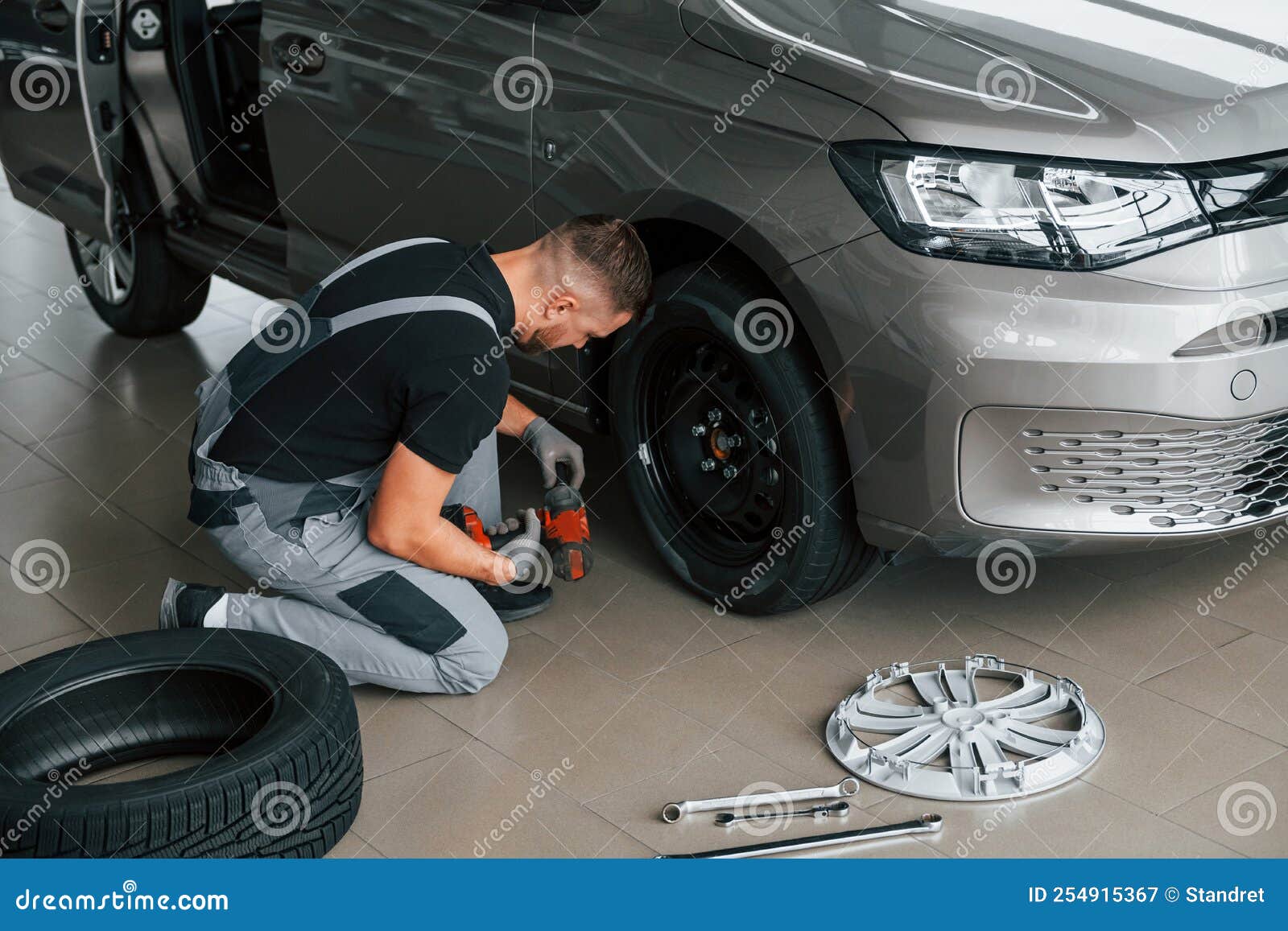 Changing of the Tires. Man in Uniform is Working in the Autosalon at ...