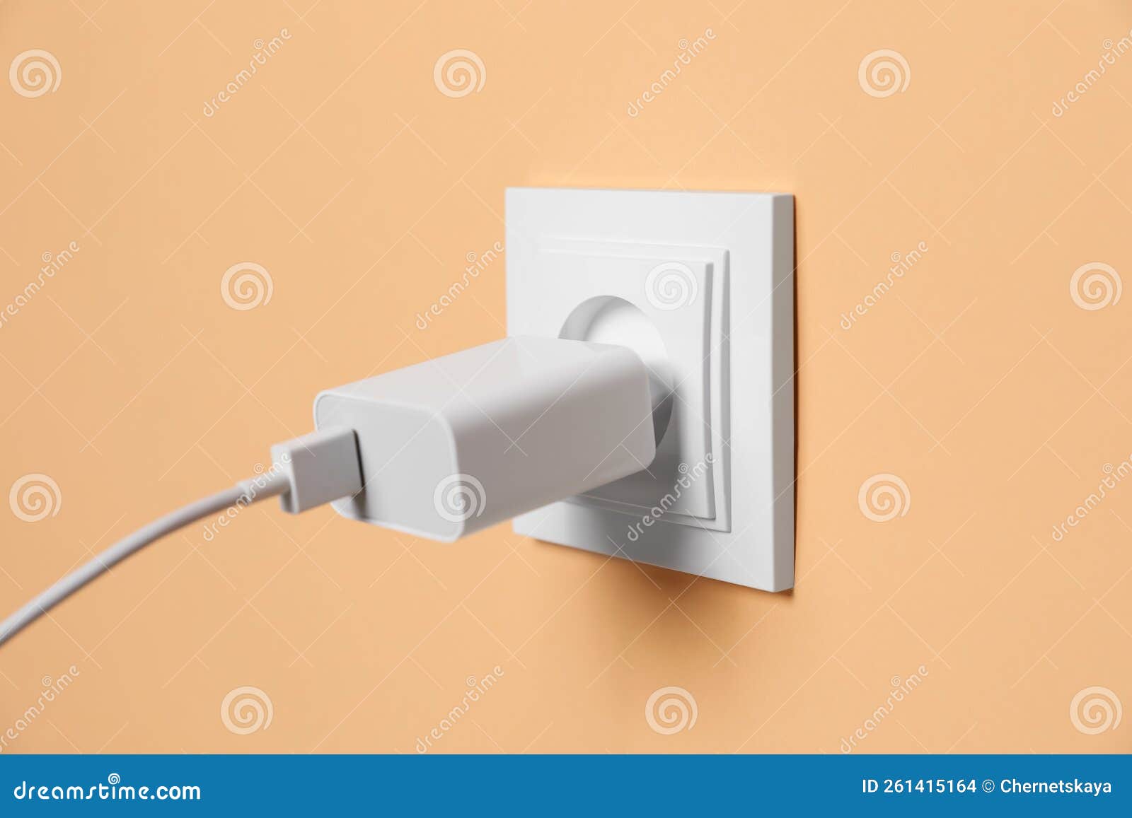 Charger Adapter Plugged into Power Socket on Pale Orange Wall, Closeup ...