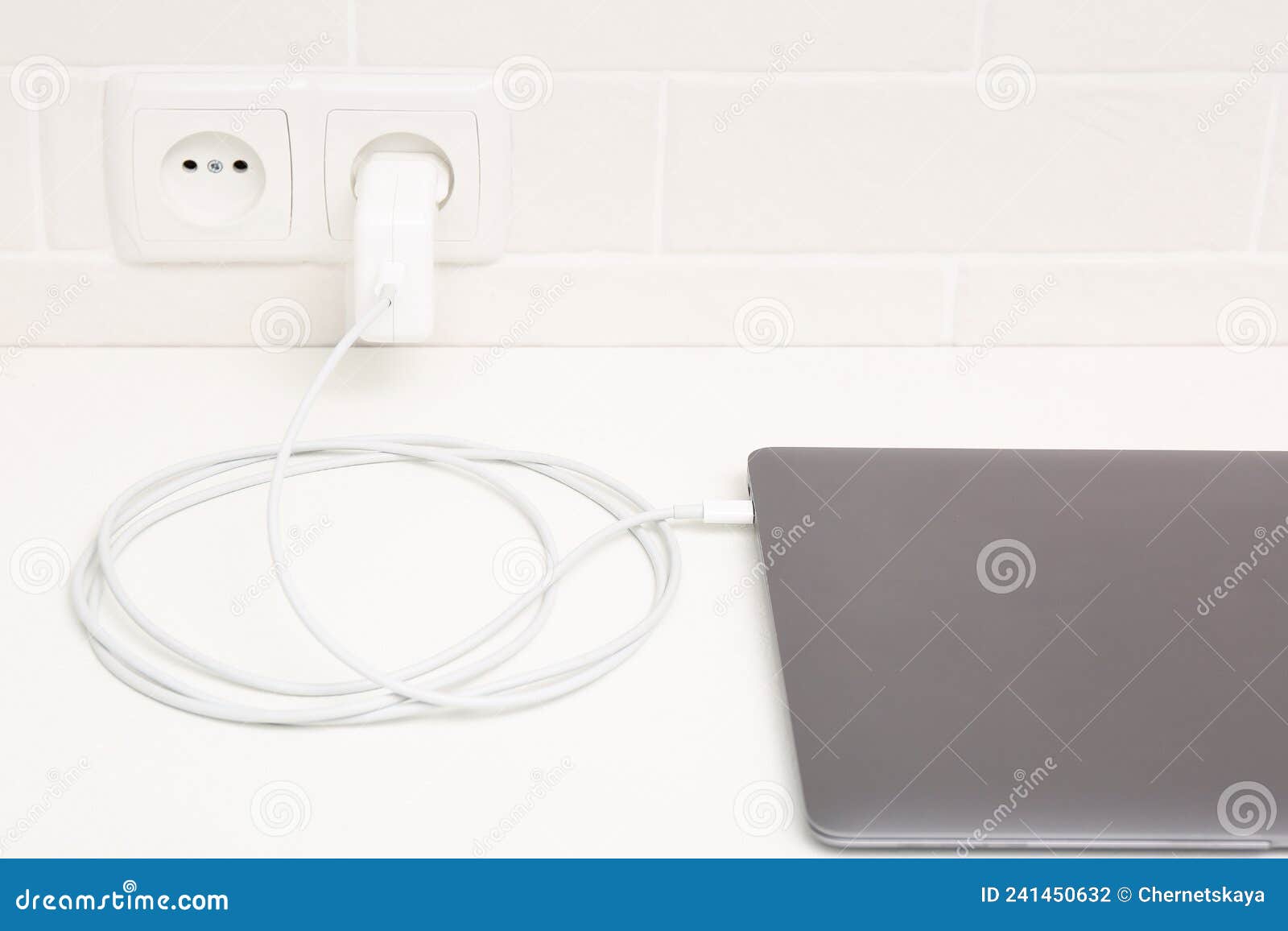 Charging Laptop with Power Adapter in Electrical Socket on White Table ...