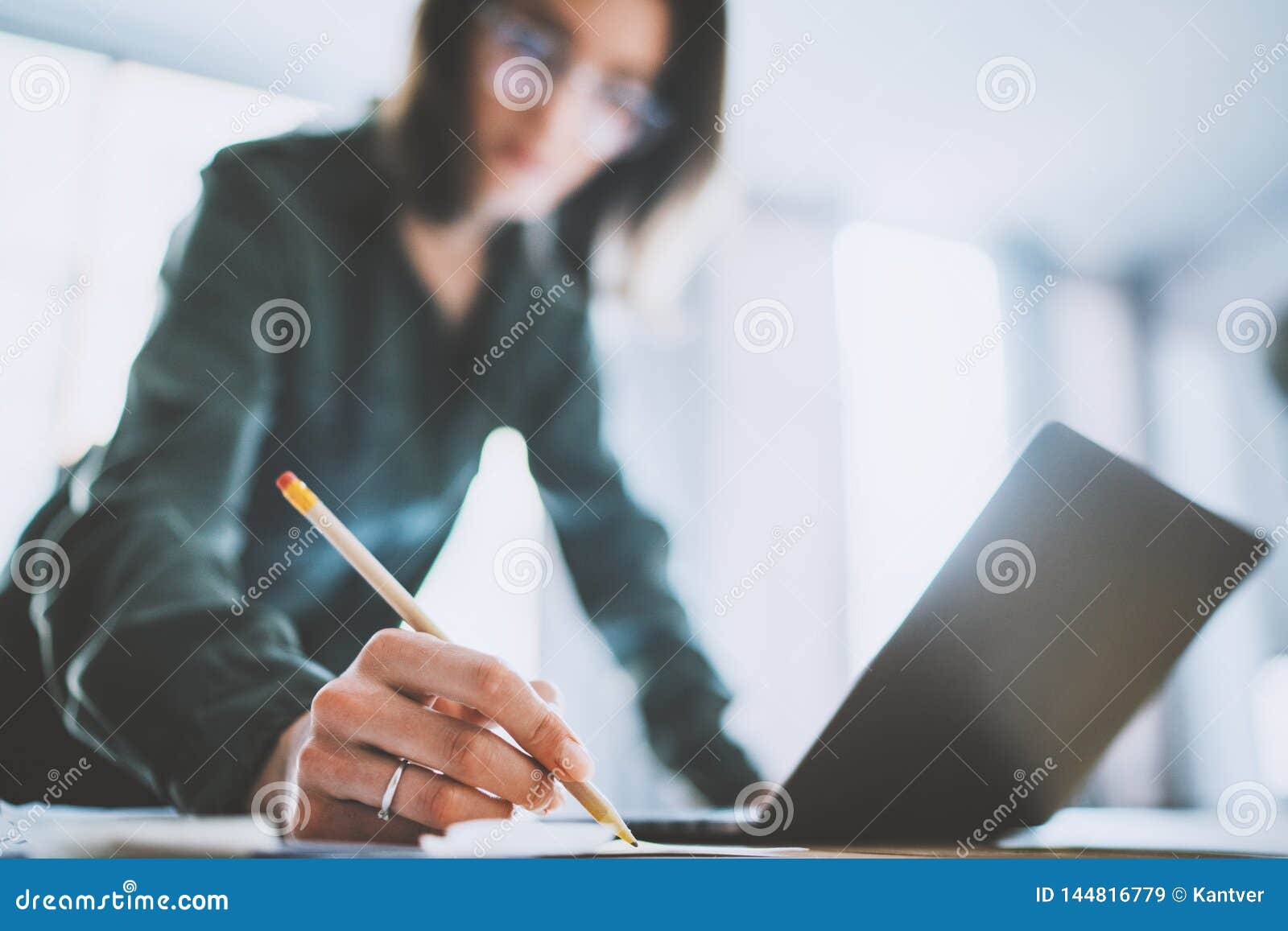 Charming Young Businesswoman Writing Something in Note Pad while ...
