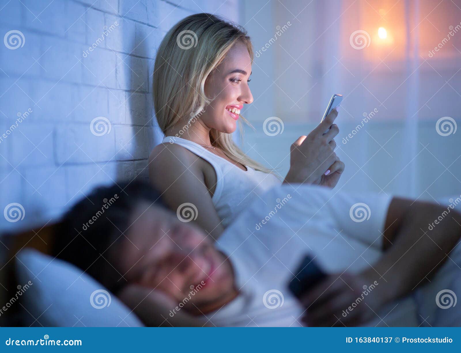 Couple Texting On Phone Lying In Bed At Night Stock Image Image Of