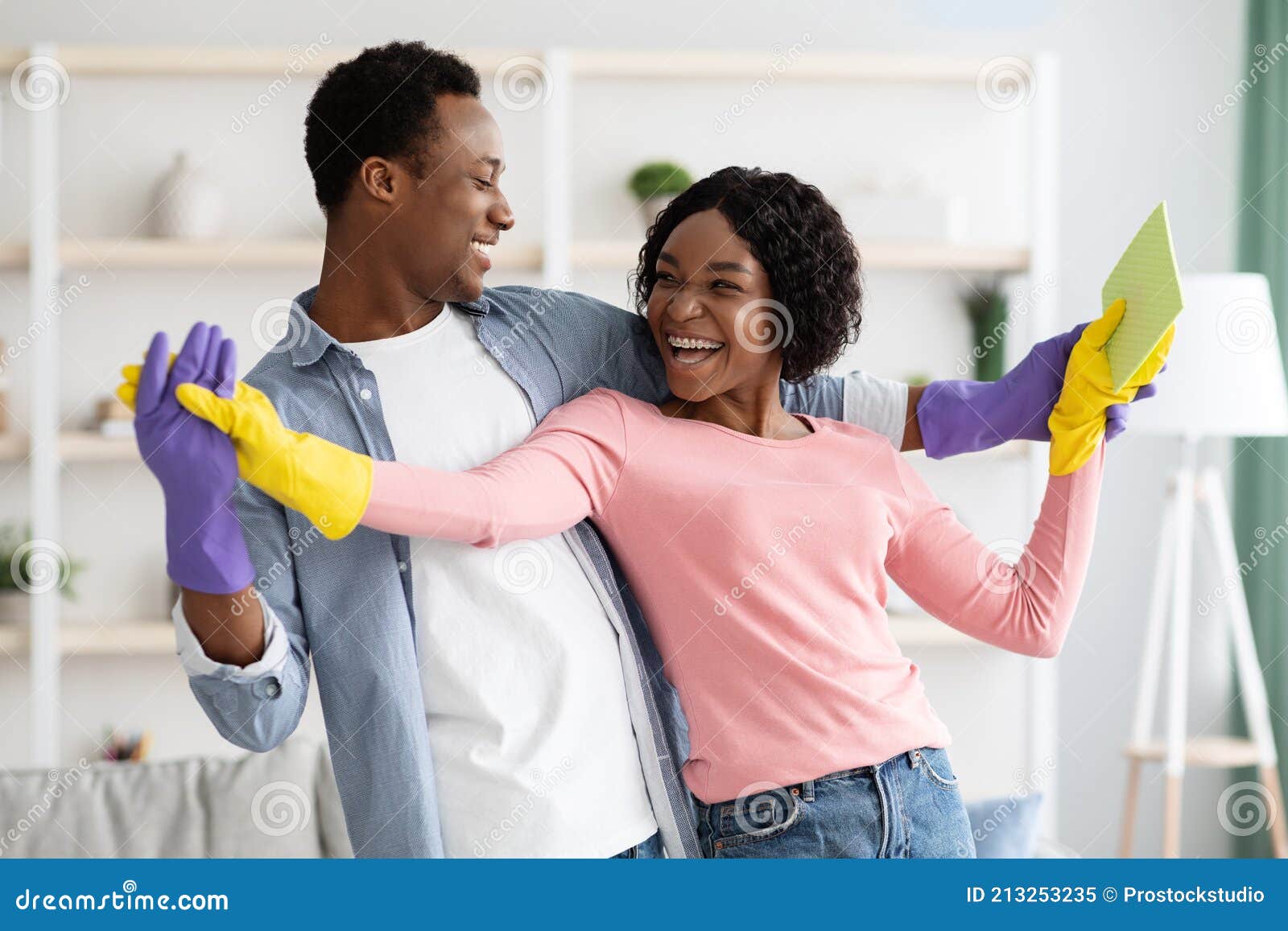 Cheerful African American Couple Dancing While Cleaning Apartment Stock