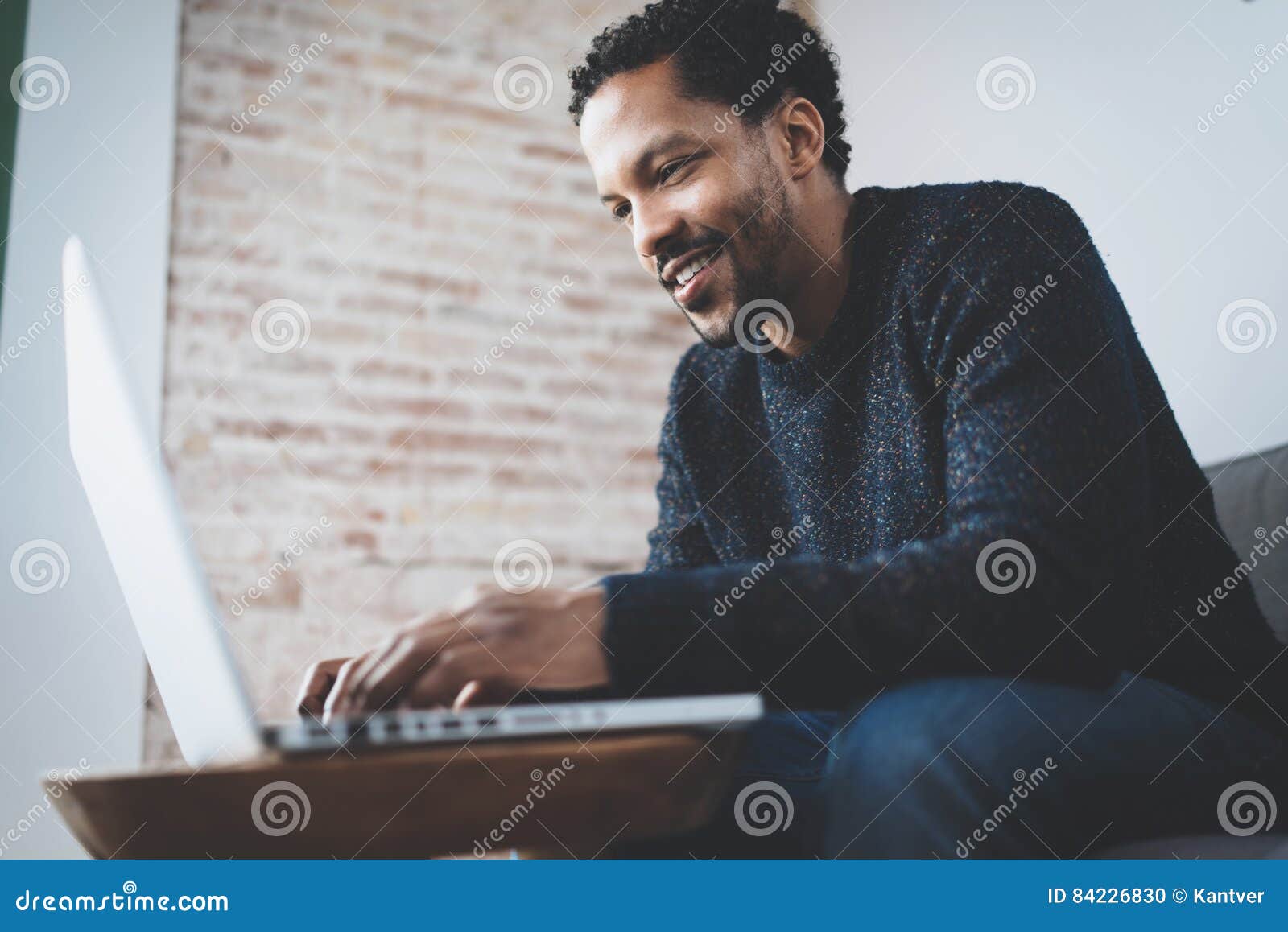Cheerful African Man Using Computer And Smiling While Sitting On The ...