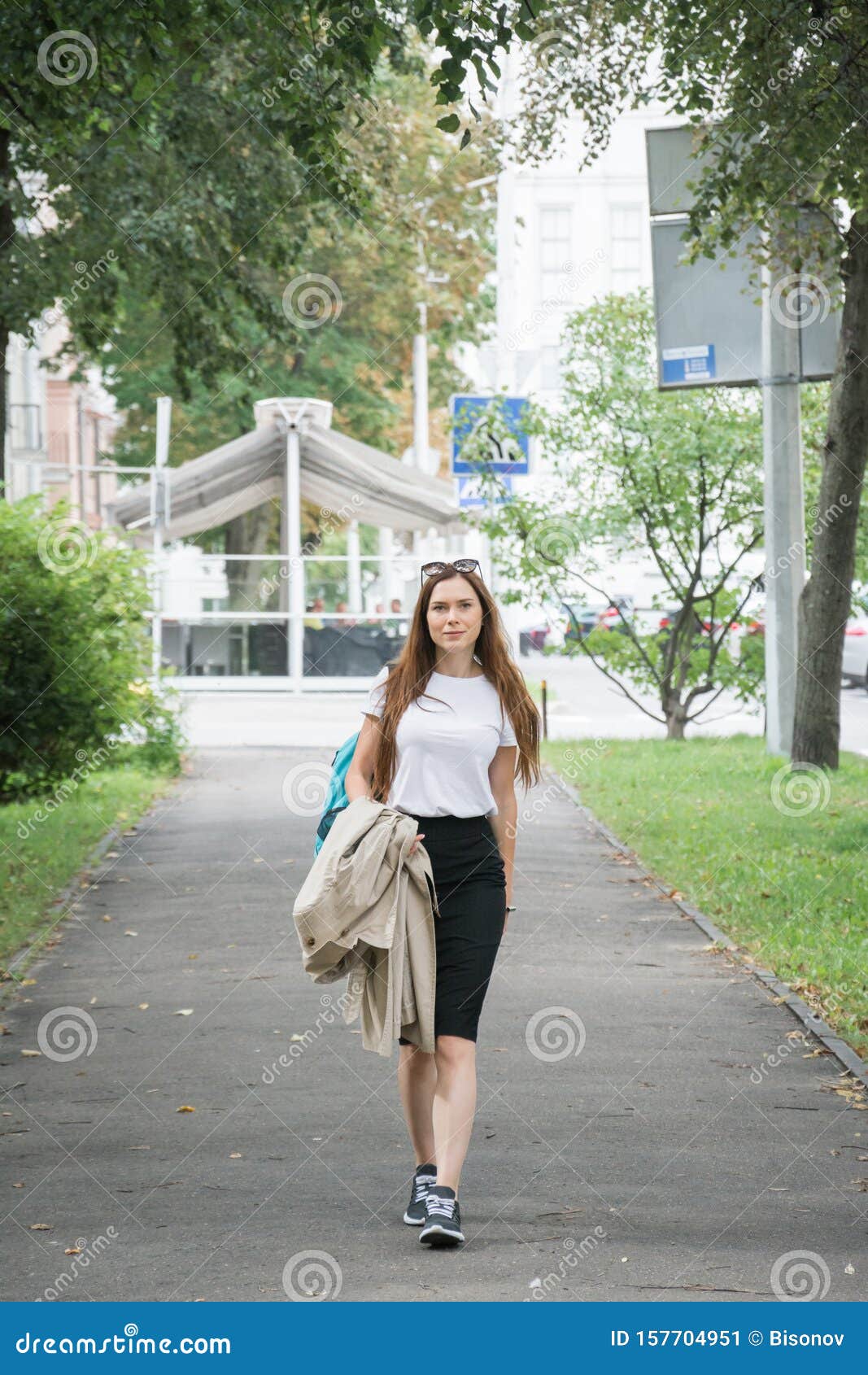 Cheerful Attractive Young Woman with Red Backpack and Book Walking in ... Cheerful Attractive Young Woman with Red Backpack and Book Walking in ...