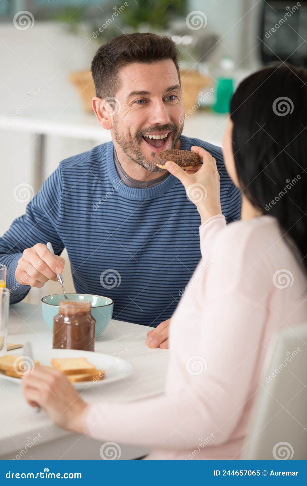 Cheerful Couple Feeding Each Other with Breakfast in Kitchen Stock ...